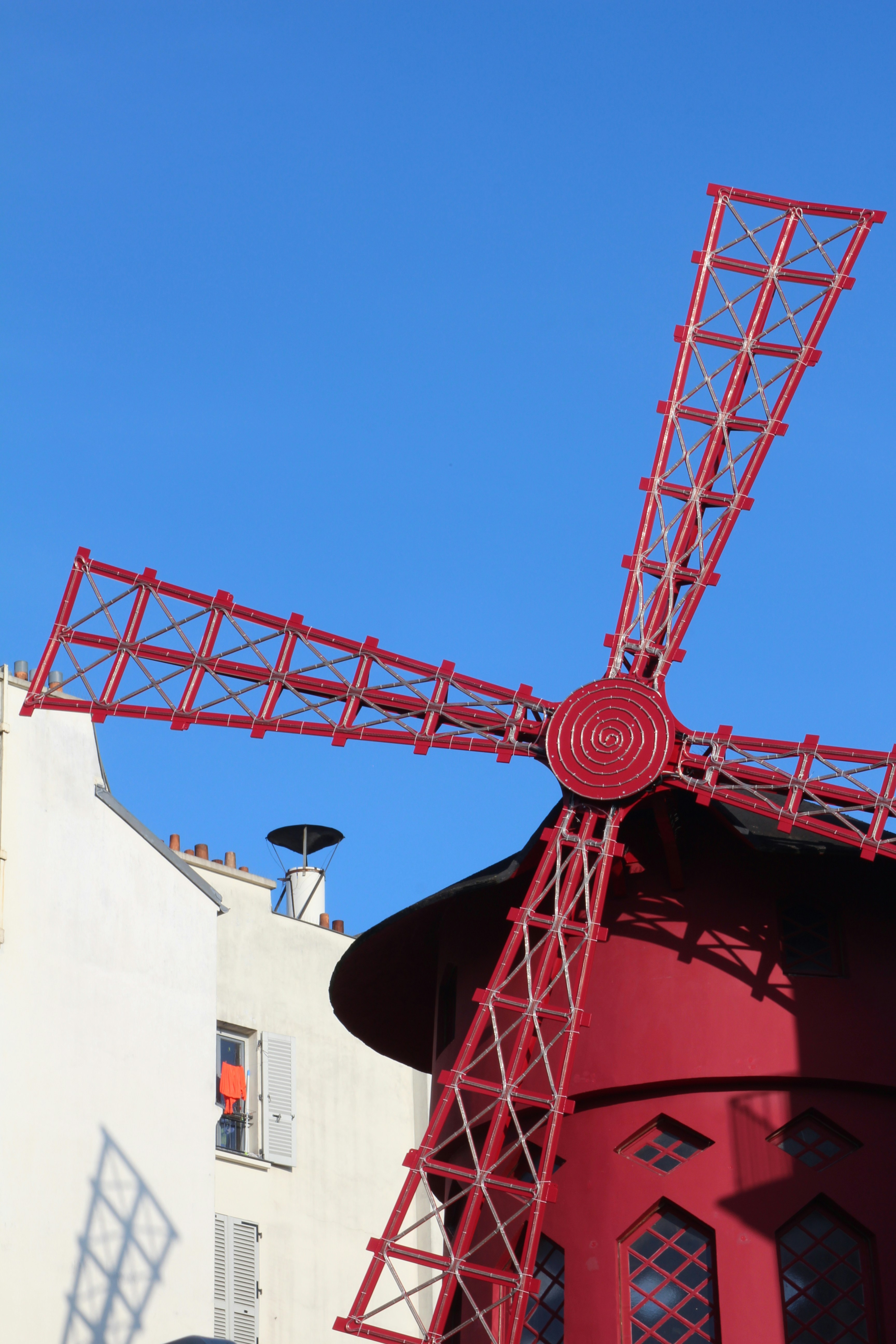 Red Windmill Blade Cuts Across a Clear Blue Sky