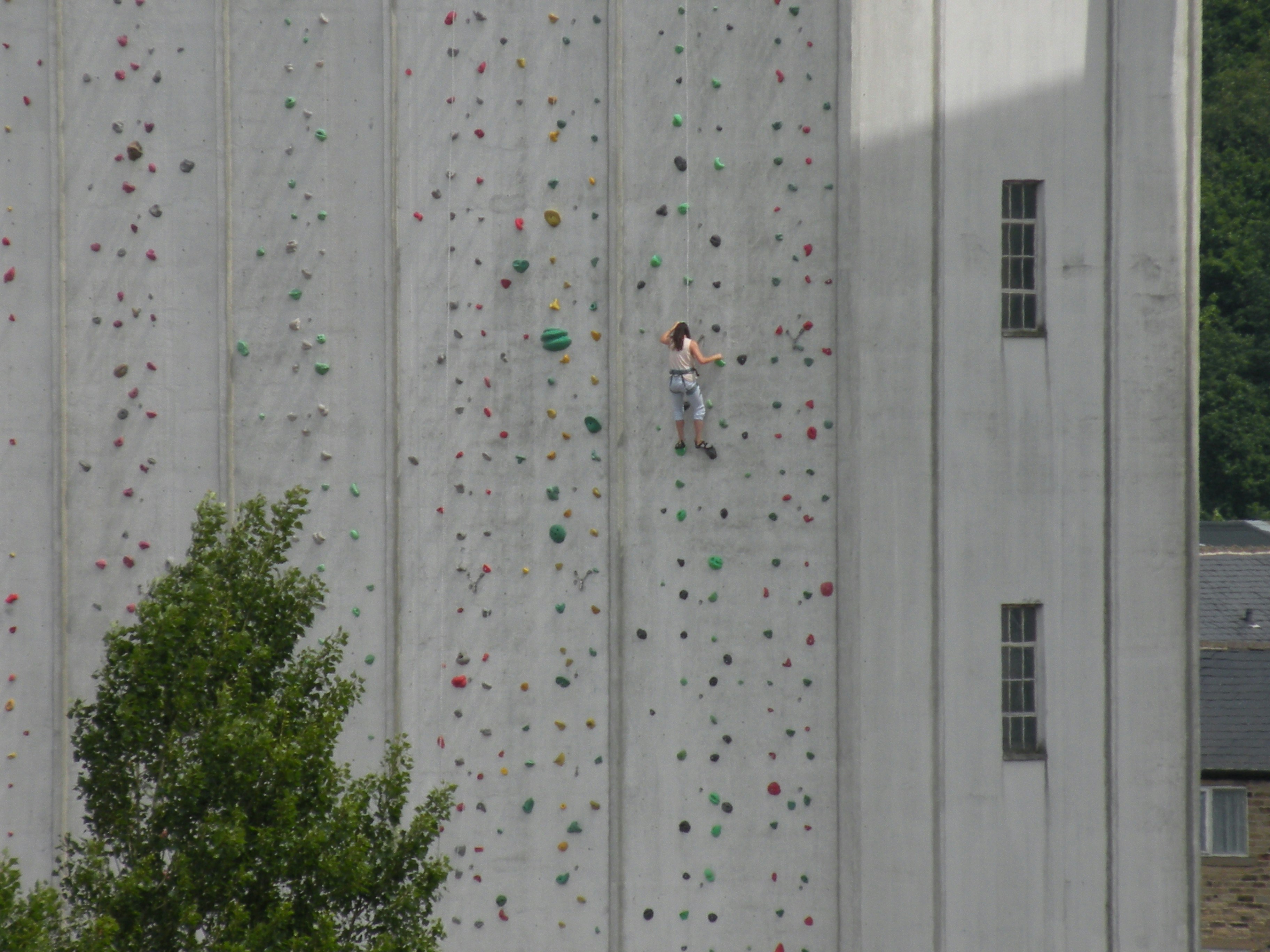 Woman climbing a tall concrete wall