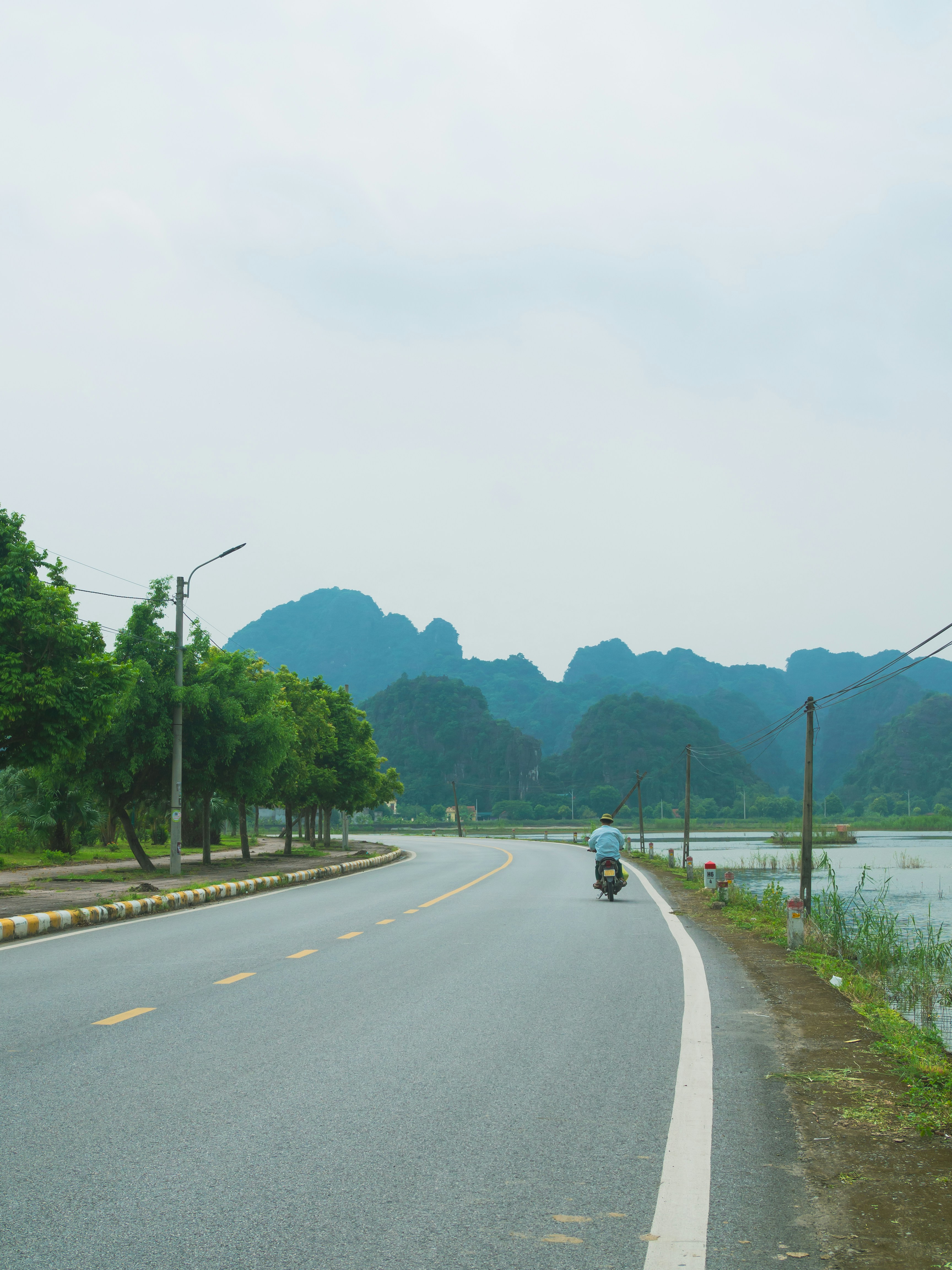 Rural Scenic Road Trek: A Lone Rider Toward Distant Limestone Peaks