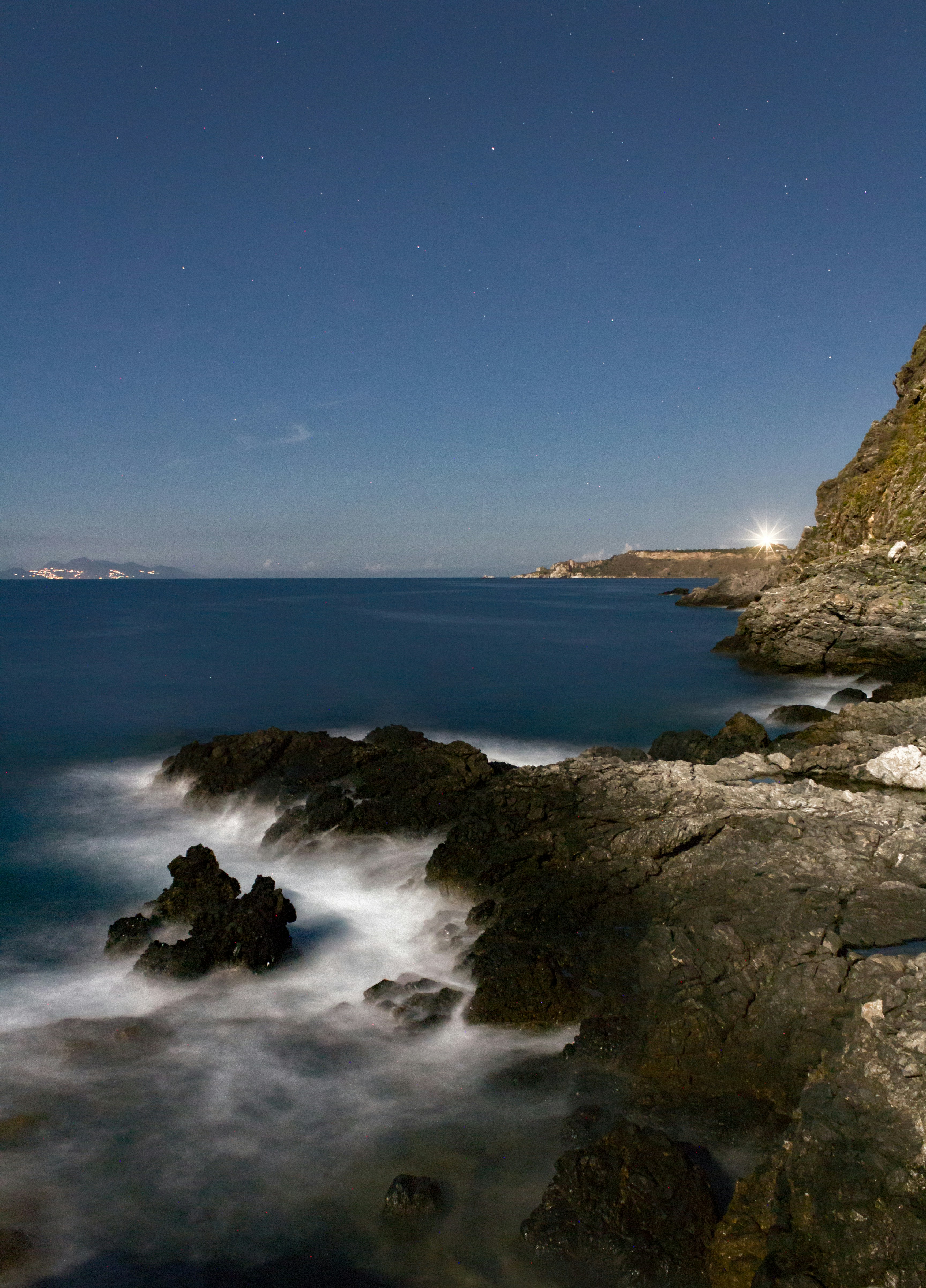 Las olas del océano iluminadas por la luna rompen contra la costa ...