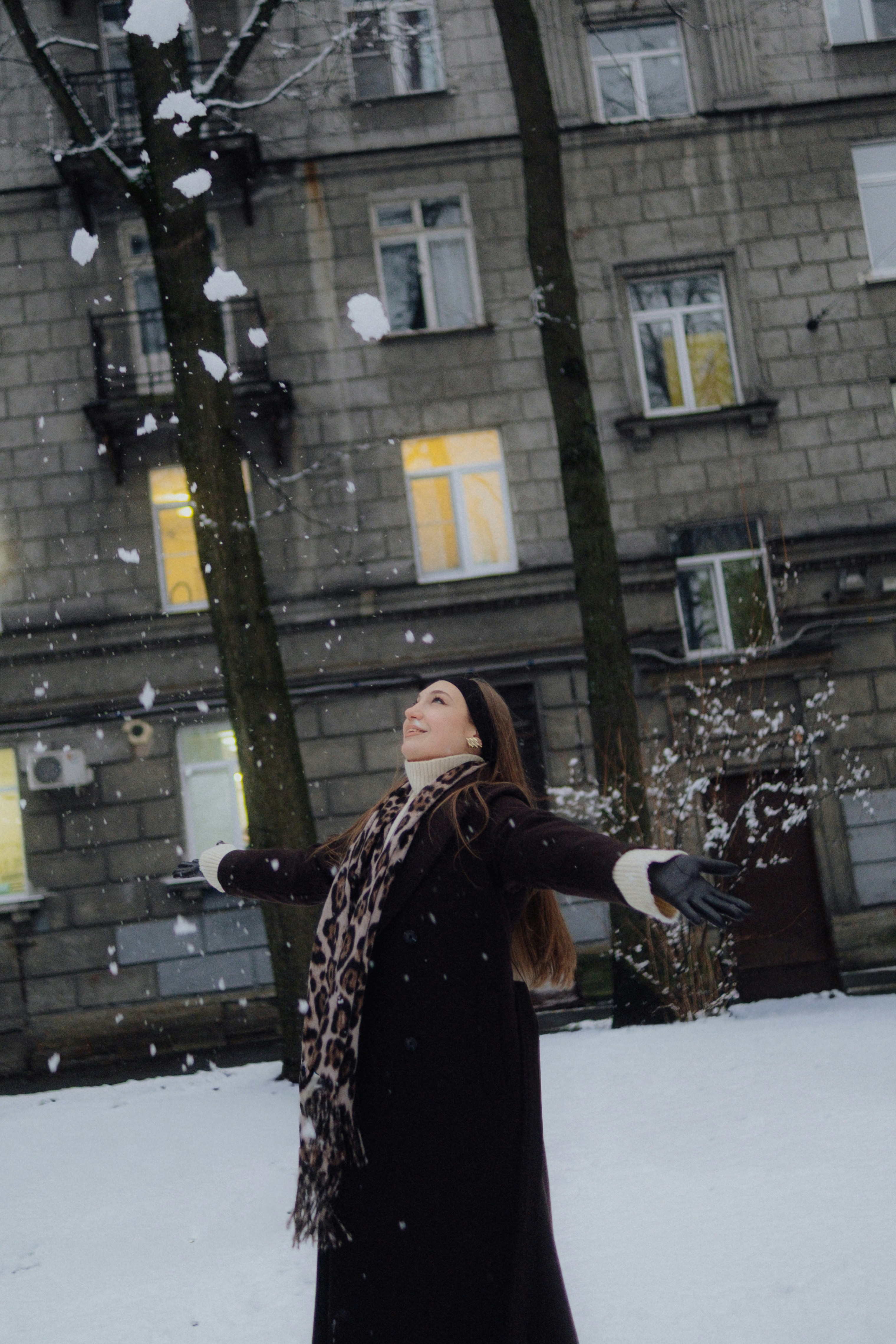 Joy in the Snow: a woman arms wide in an urban courtyard