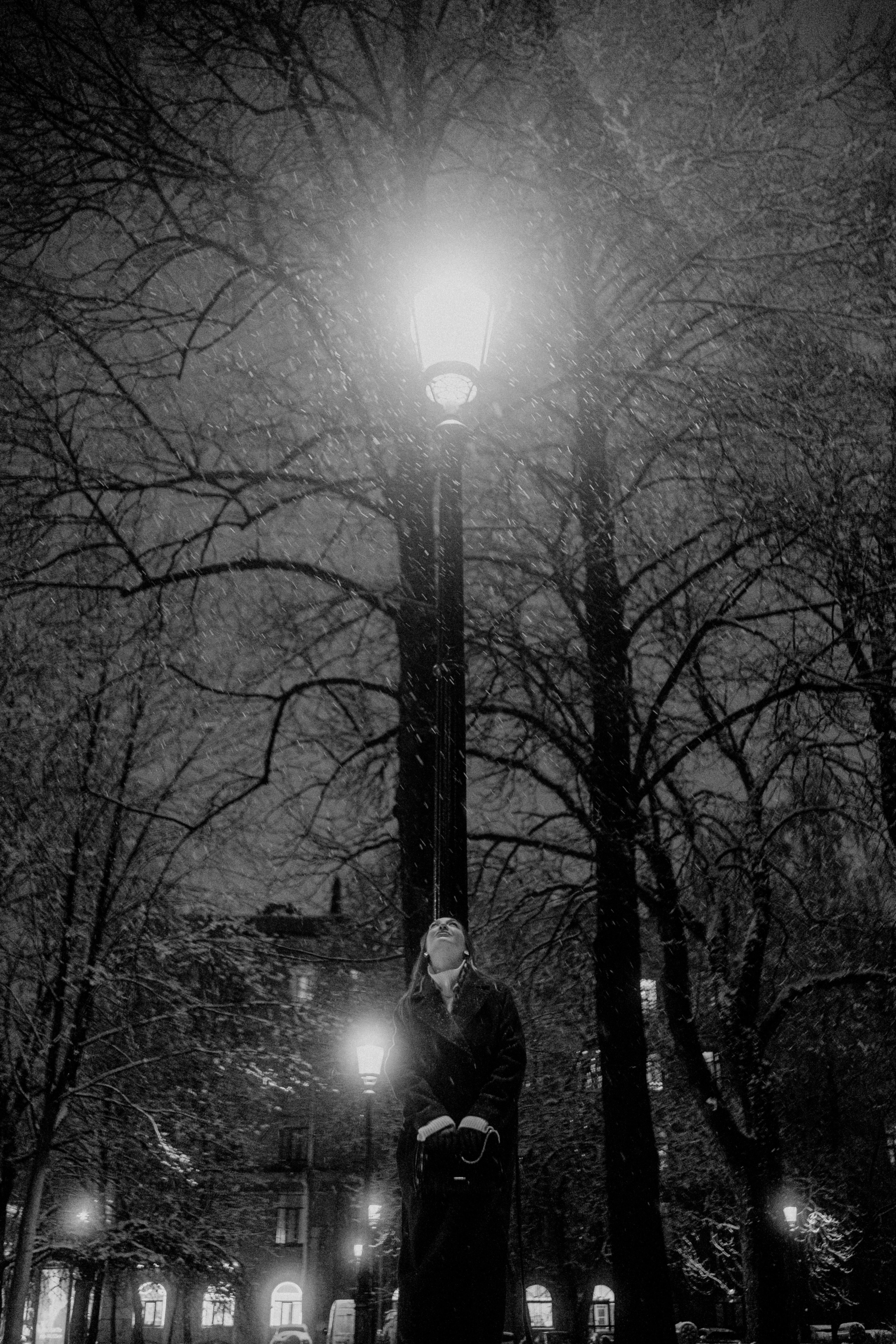 Nighttime Lantern: A solitary figure beneath a snowy streetlamp