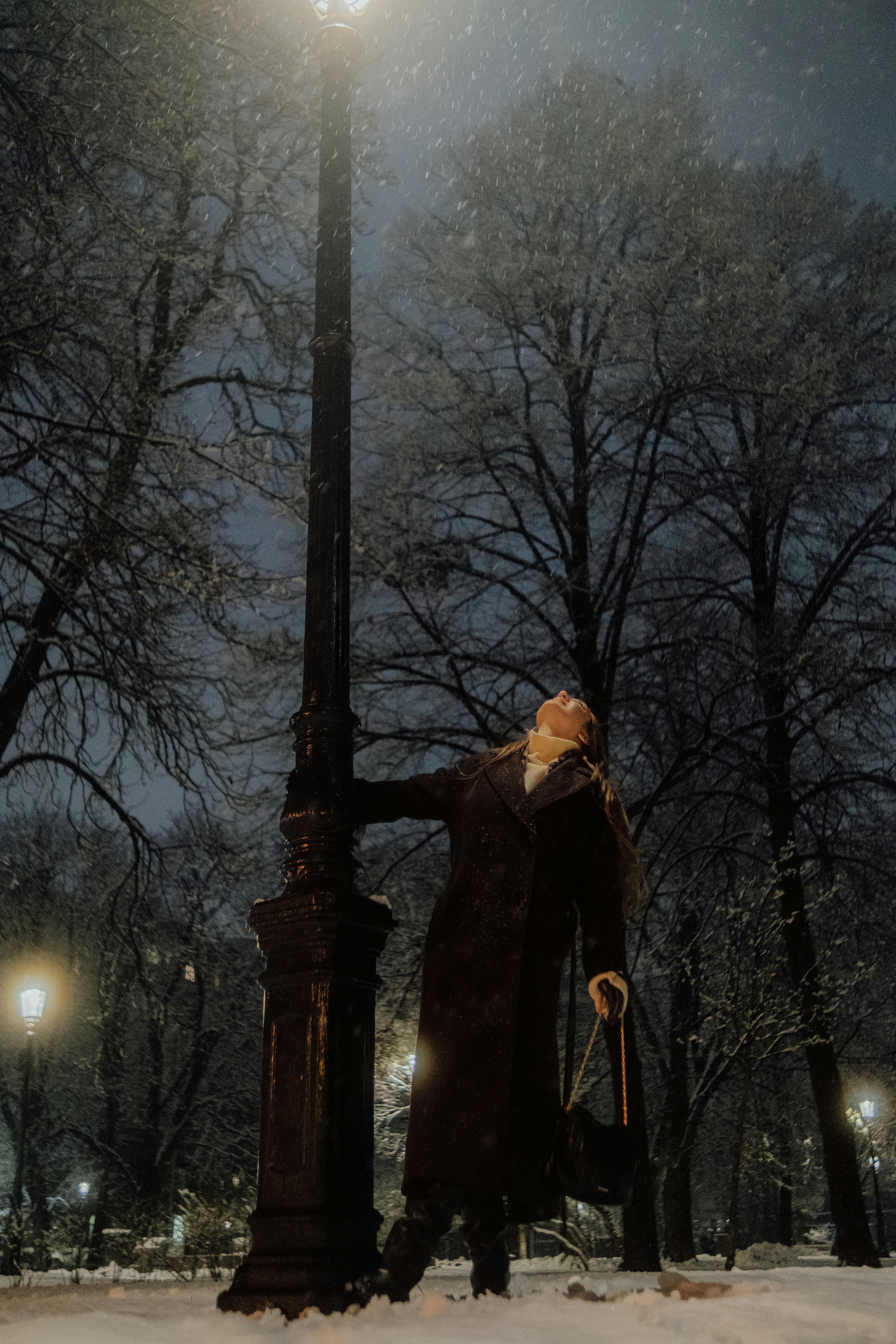 Moonlit Snow: A Woman Reaches Toward the Lamp Post in Winter Night