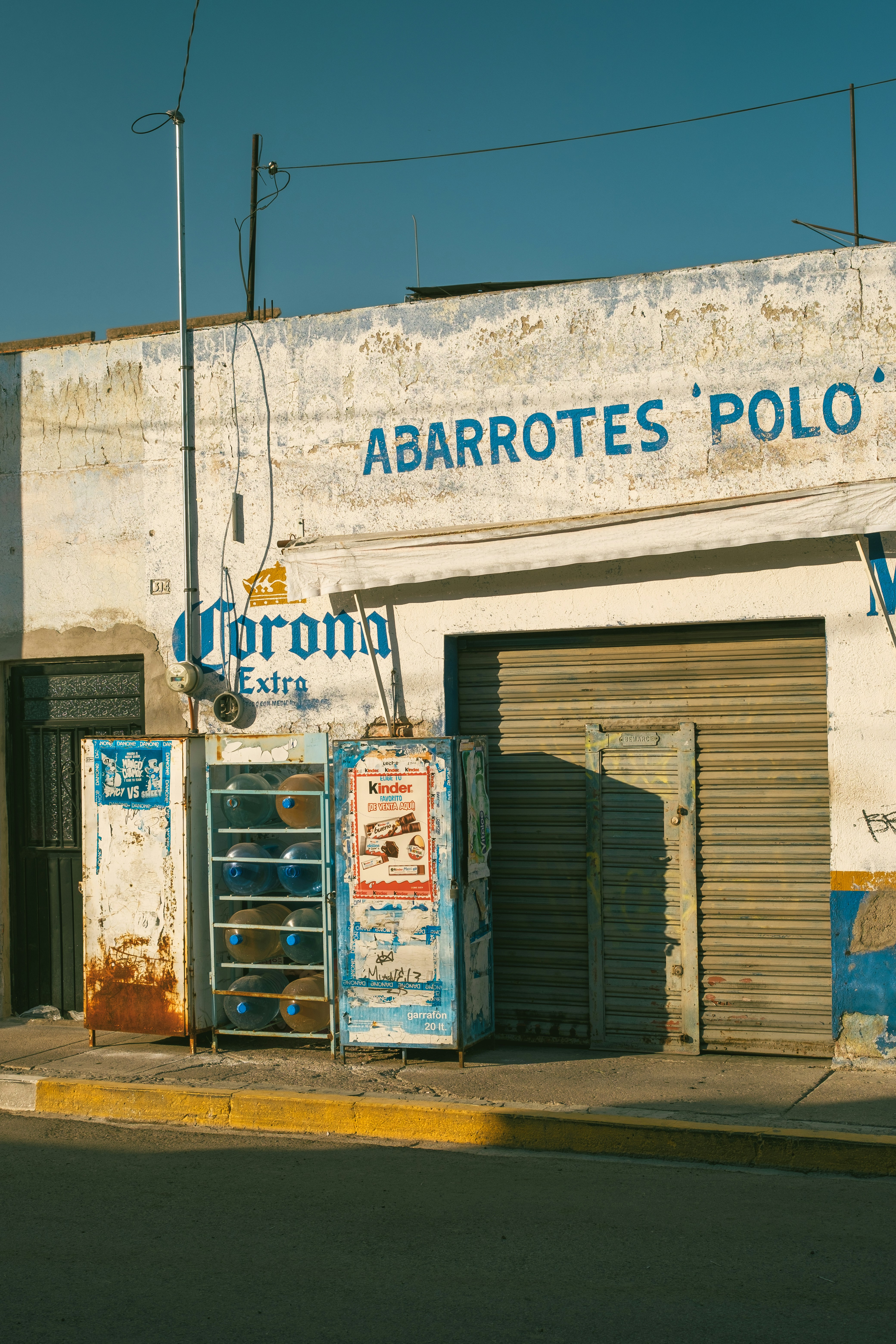 Weathered storefront with blue signage and vending machines at dusk