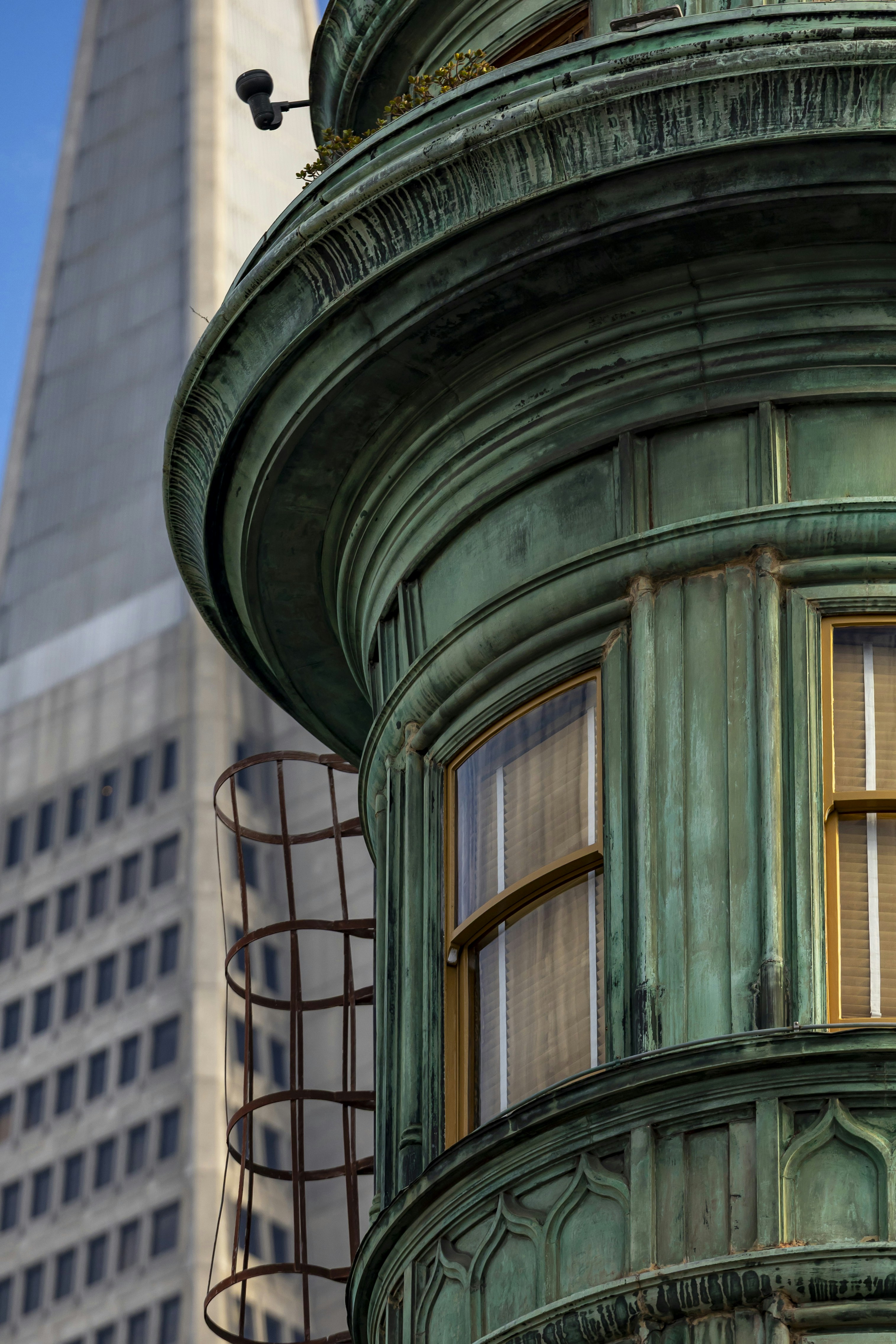 Verdigris Corner: The Curved Facade of a Historic Green Building Near a Modern Silhouette