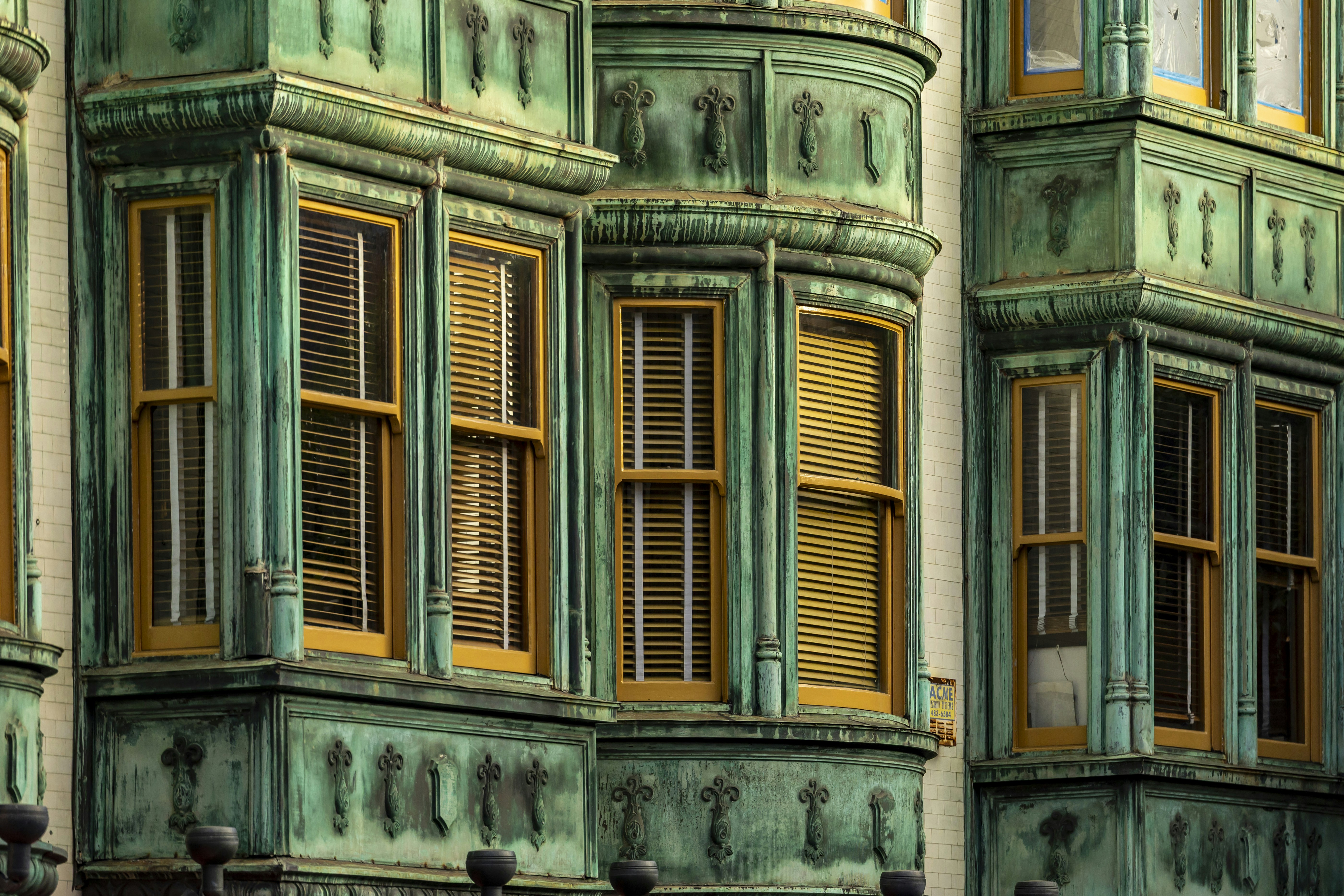 Verdigris Facade: Sunlit Windows and Ornate Carving