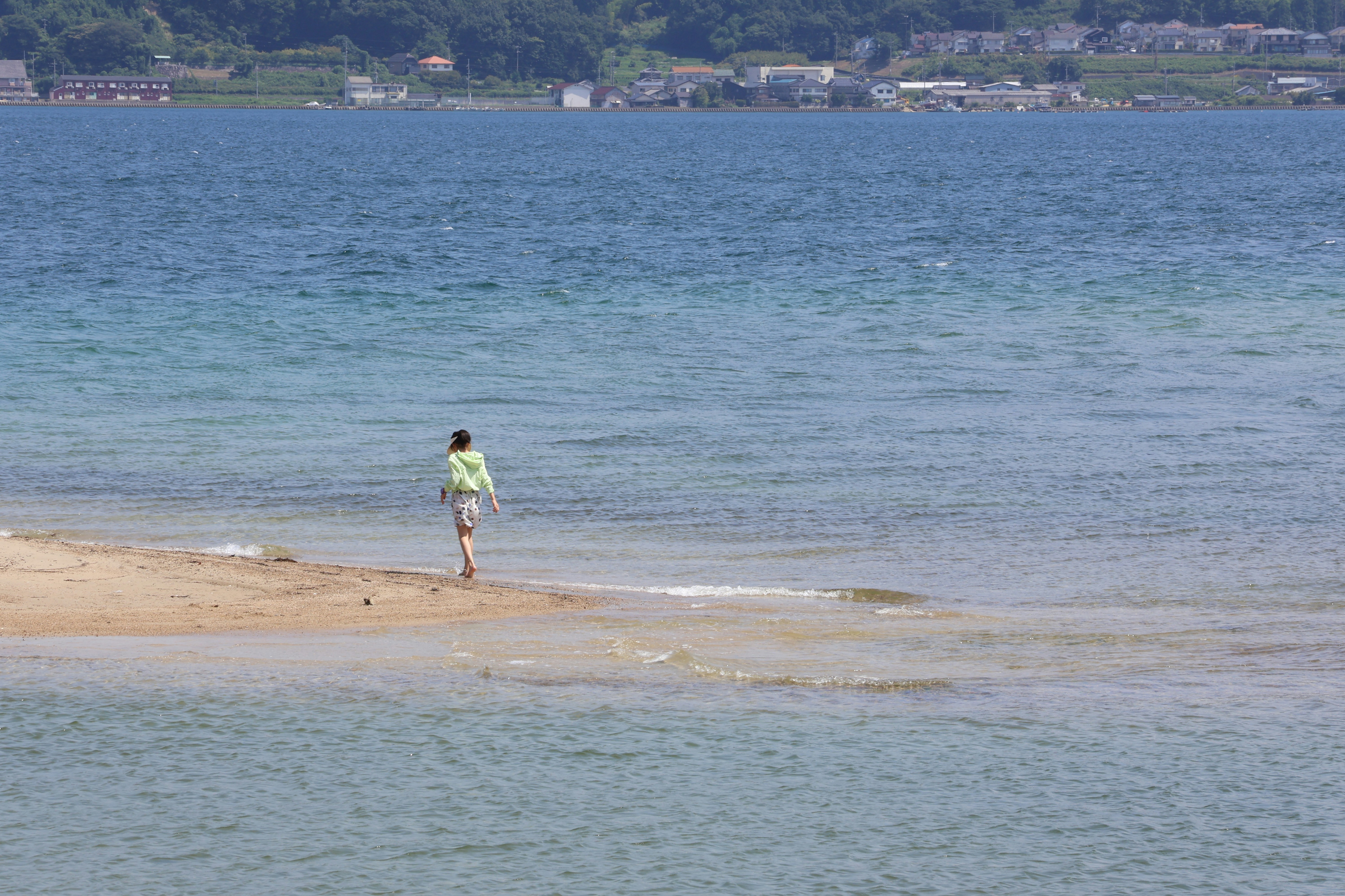 Coastal stroll: a lone swimmer treads a quiet low-tide path