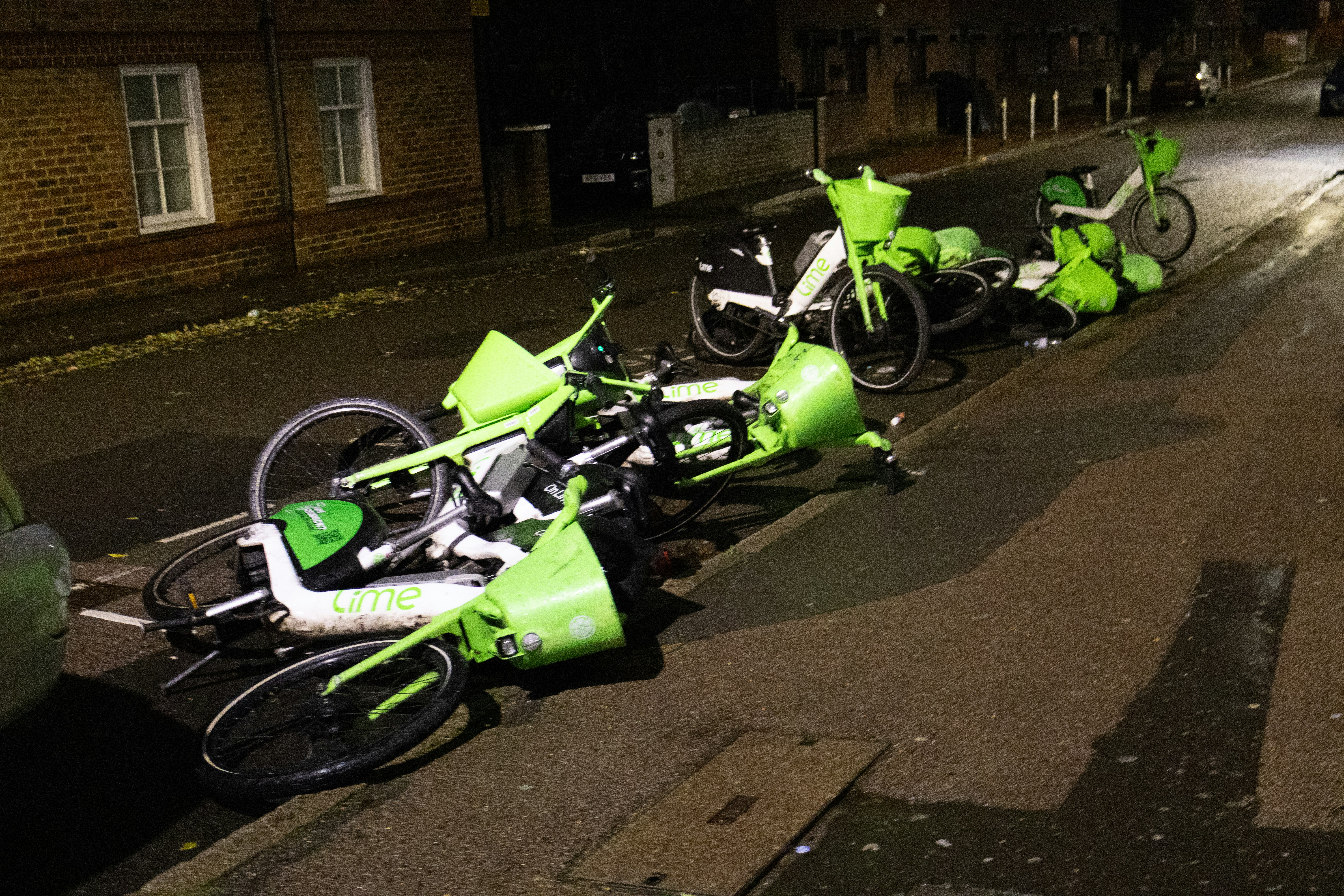 Emerald Arc: Abandoned Lime Motorbikes on a Damp Urban Street