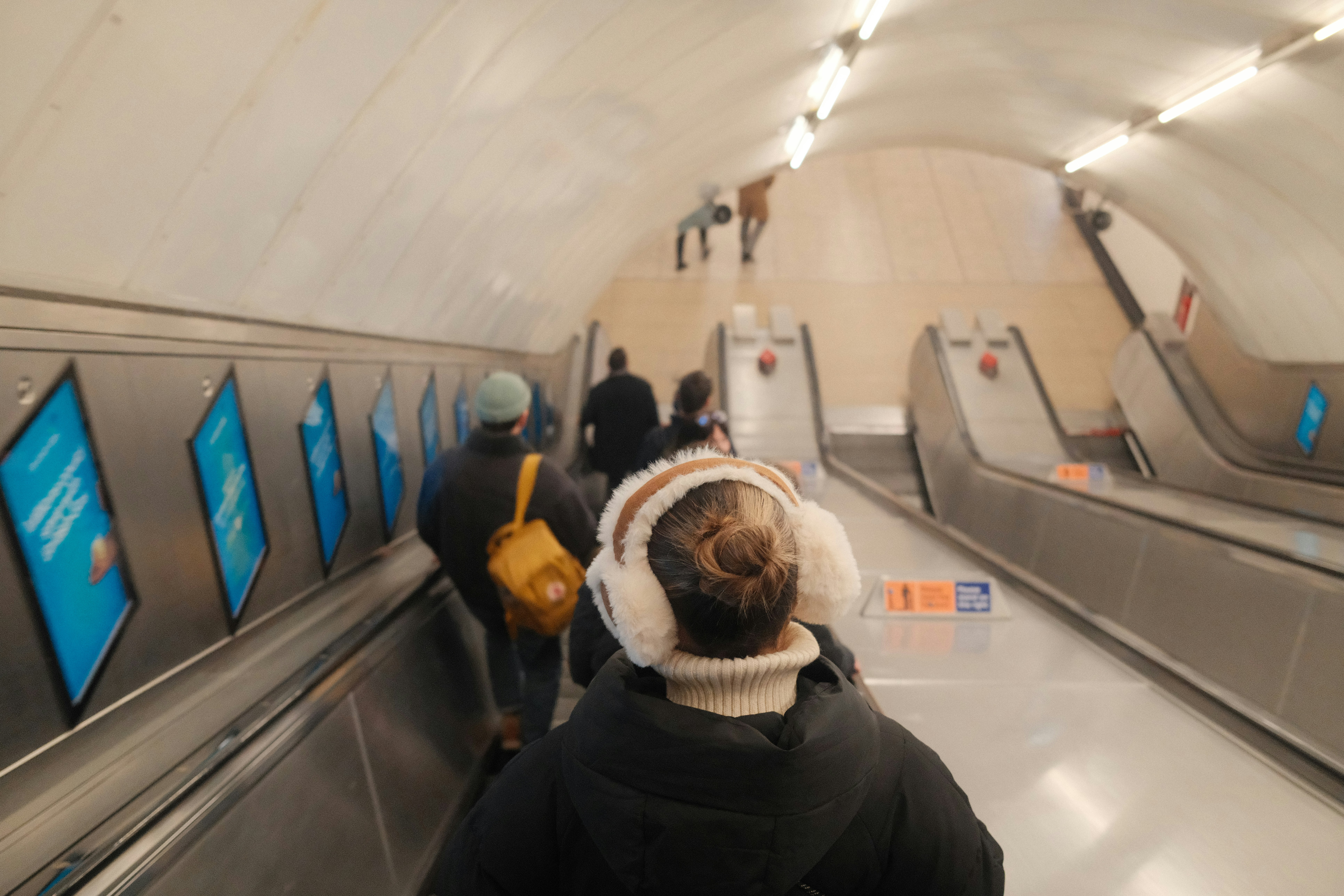 Backlit Ascent: A Traveler Climbs the Subway's Quiet Corridor