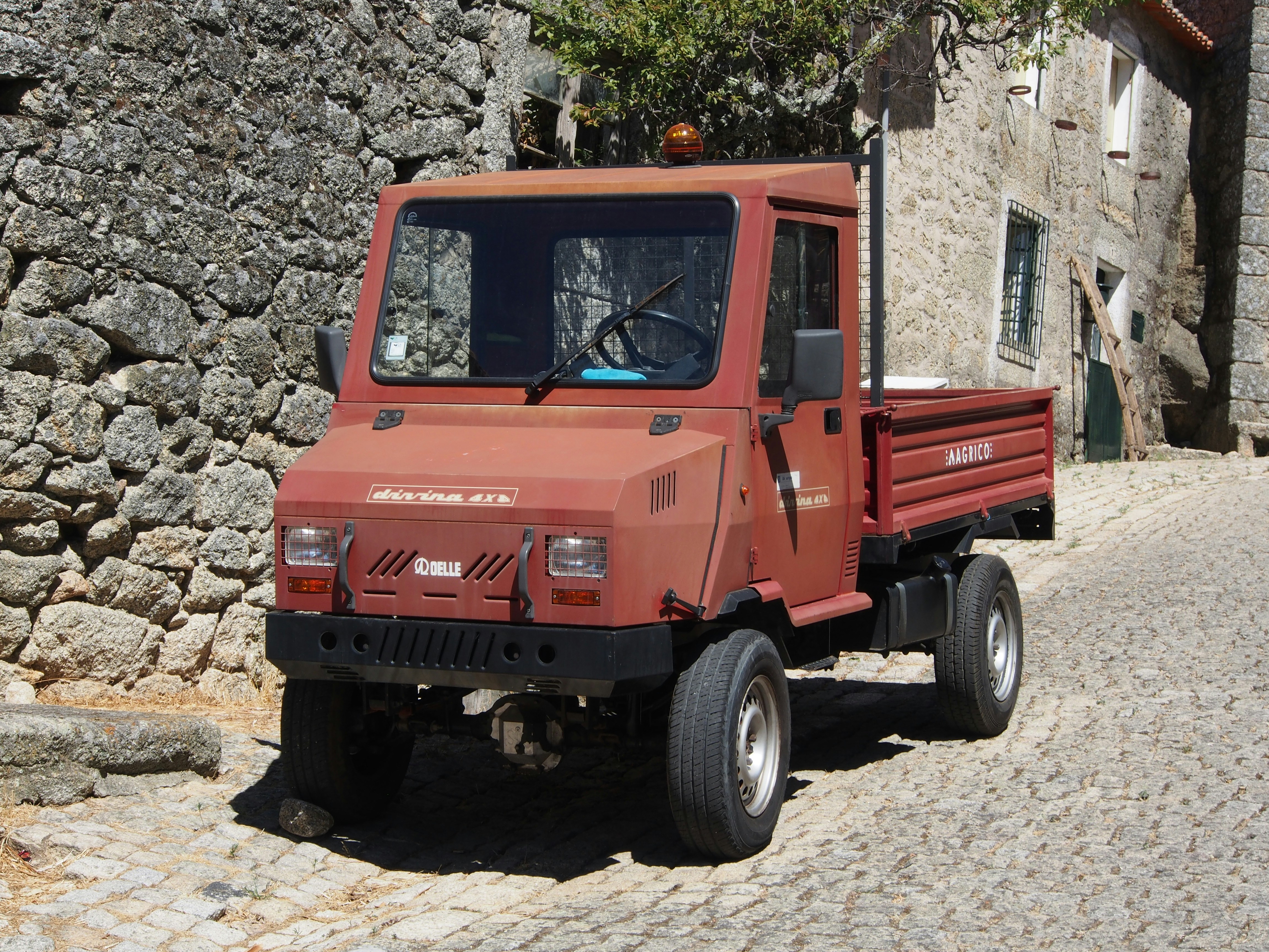 Red utility truck guarding a cobbled village alley