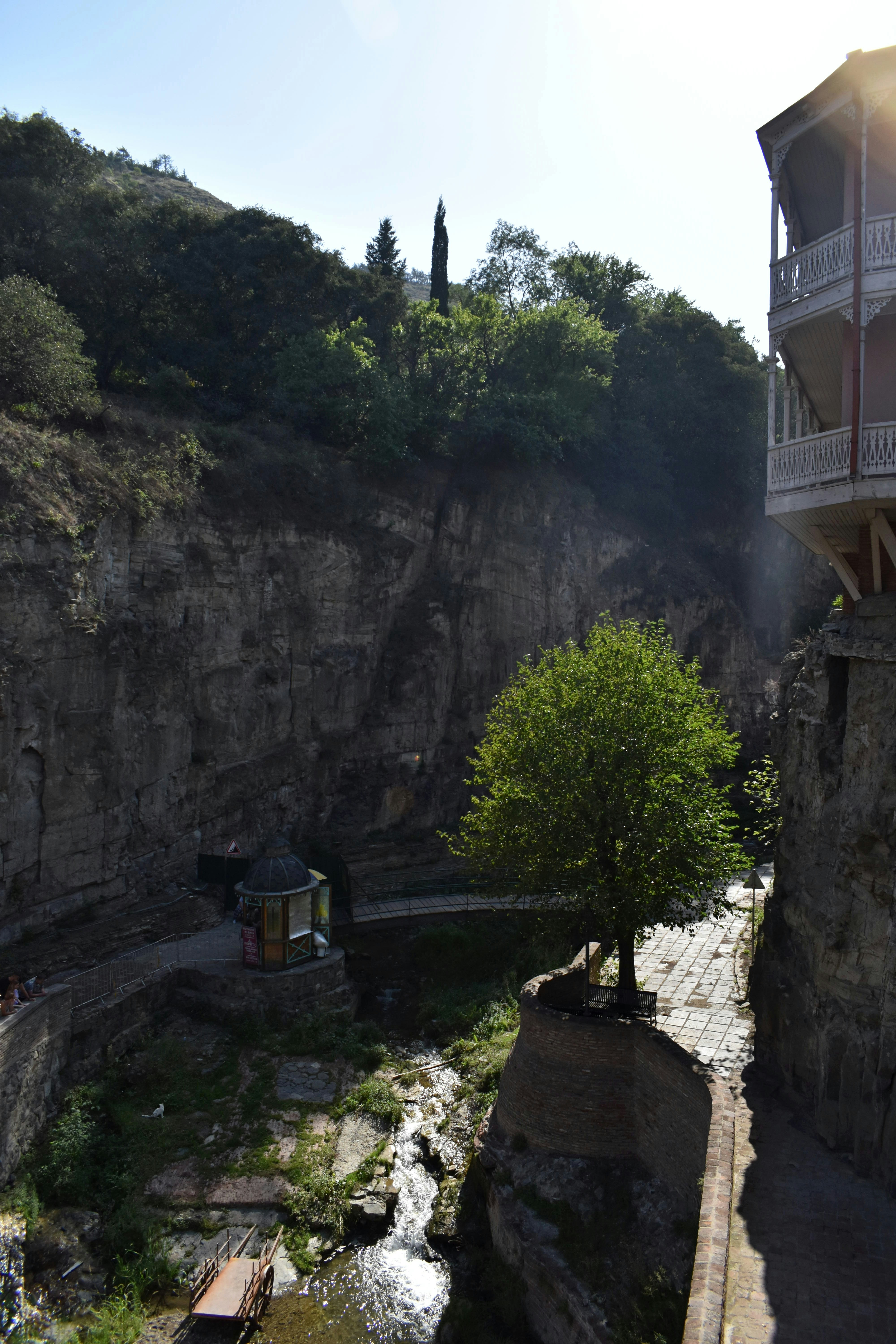 Cliffside Walkway: A Sunlit Tree Framed by a Historic Balcony