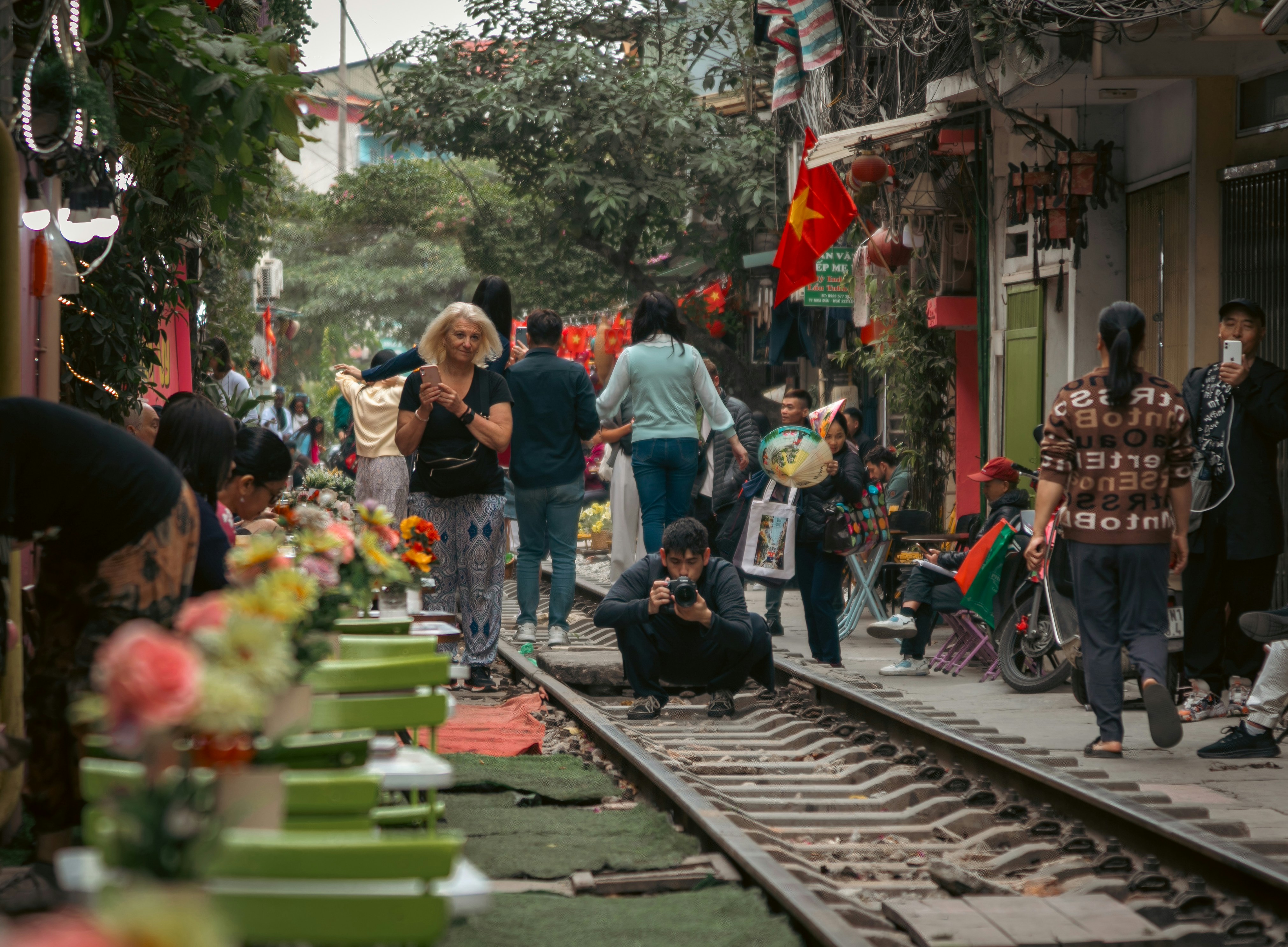 Onlookers and a photographer converge along a lively street railway
