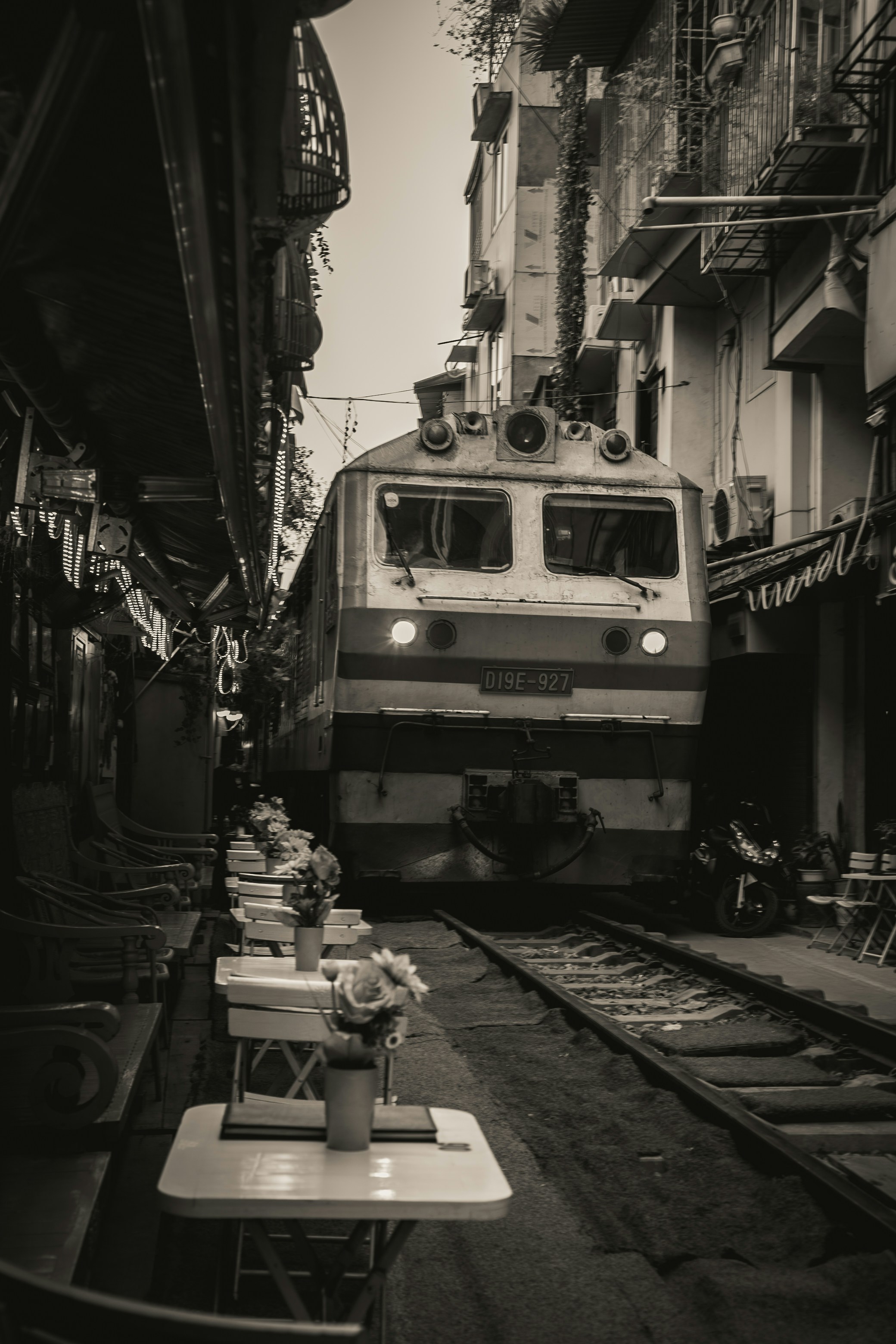 Narrow-rail Café Pause: A Trainfront Bistro in Monochrome Alley
