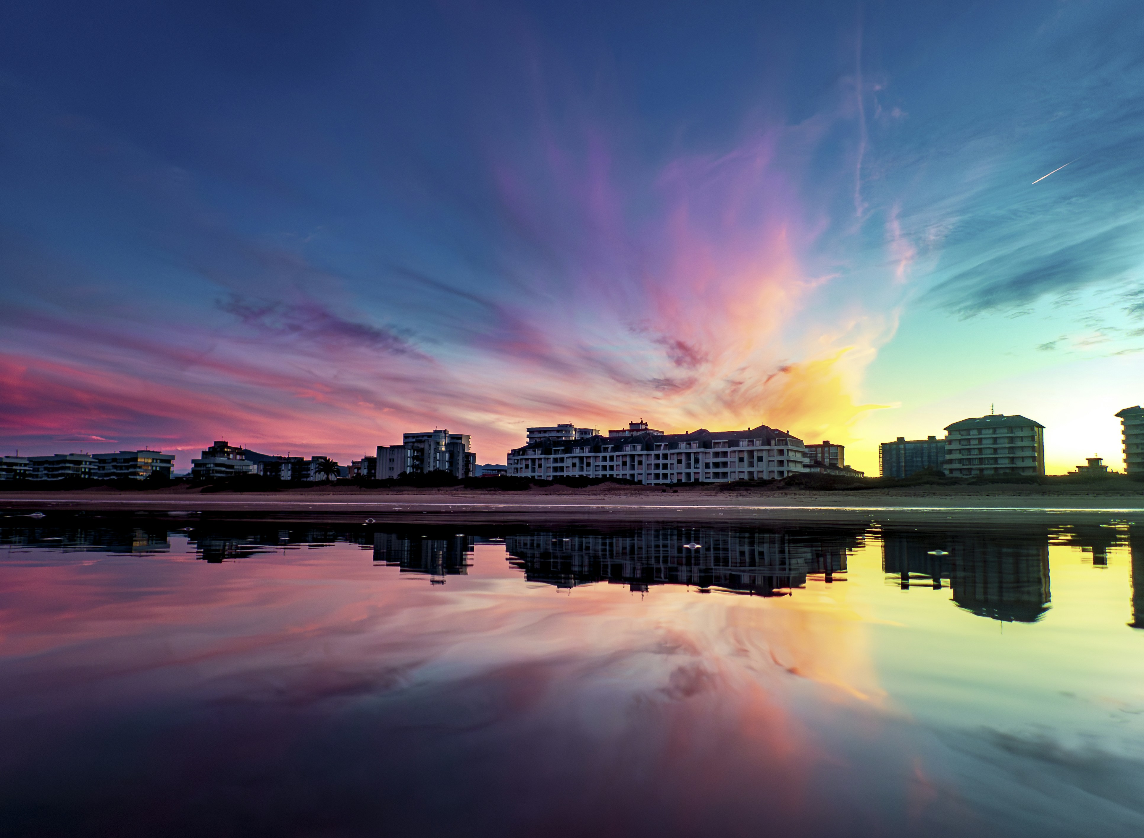 Perfect stillness as the wet sand reflects a sunset that holds the full spectrum of the rainbow.