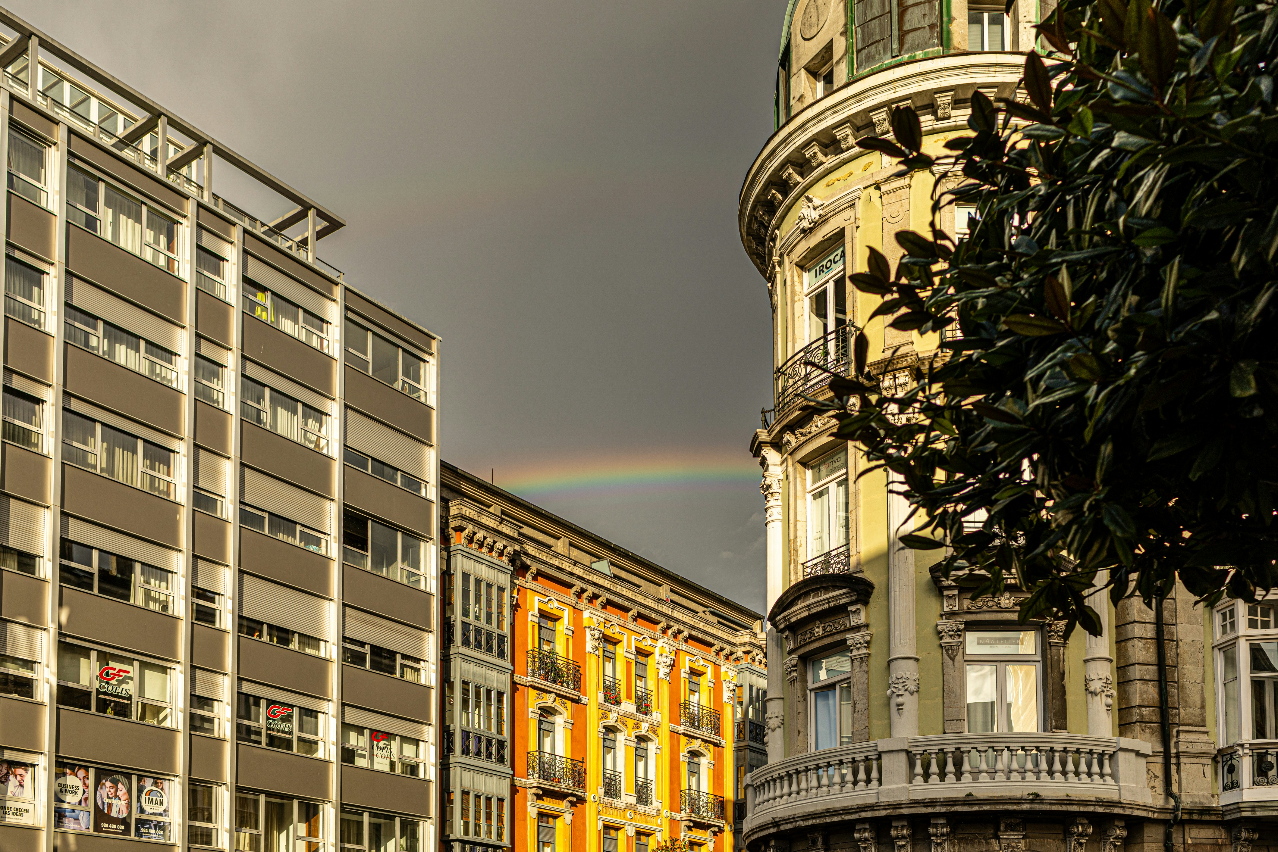 Rainbow over the urban edge: sunlit yellow façade framed by modern and curved architecture