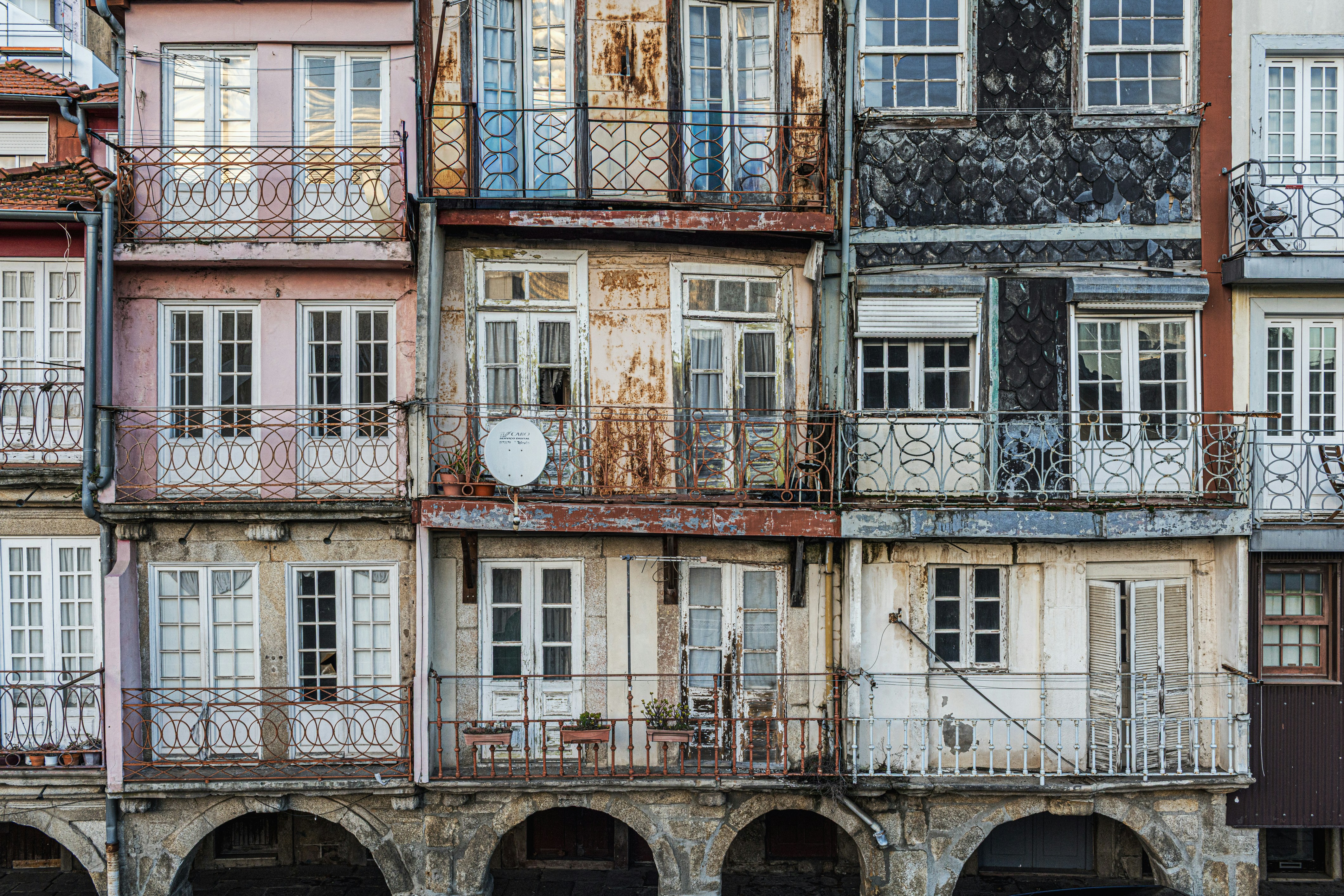 Historic Portuguese buildings with ornate iron balconies and aging facades in Porto's Ribeira district.