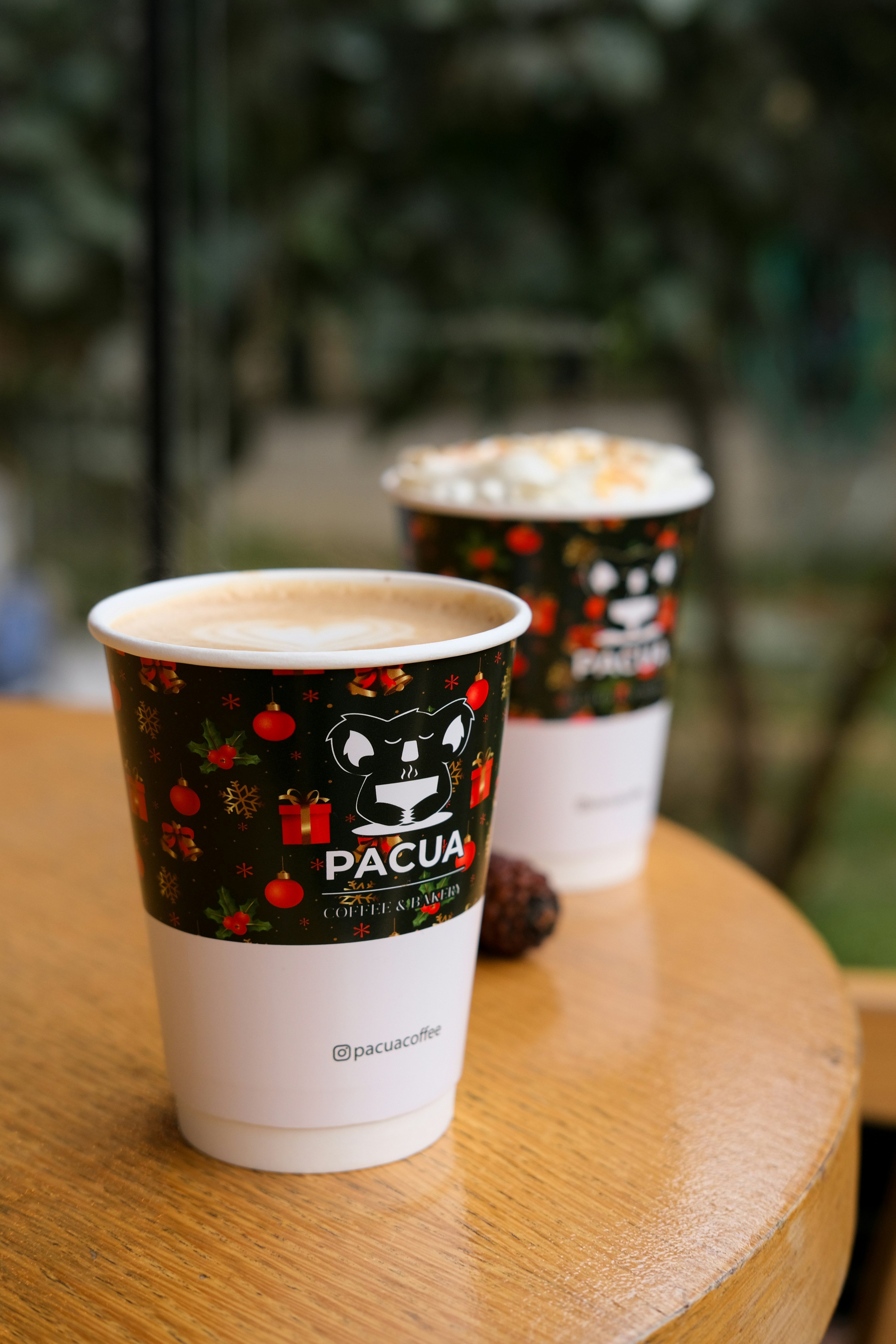 Foamy Caramel Warmth: A Duo of Holiday Coffee Cups on a Wooden Table