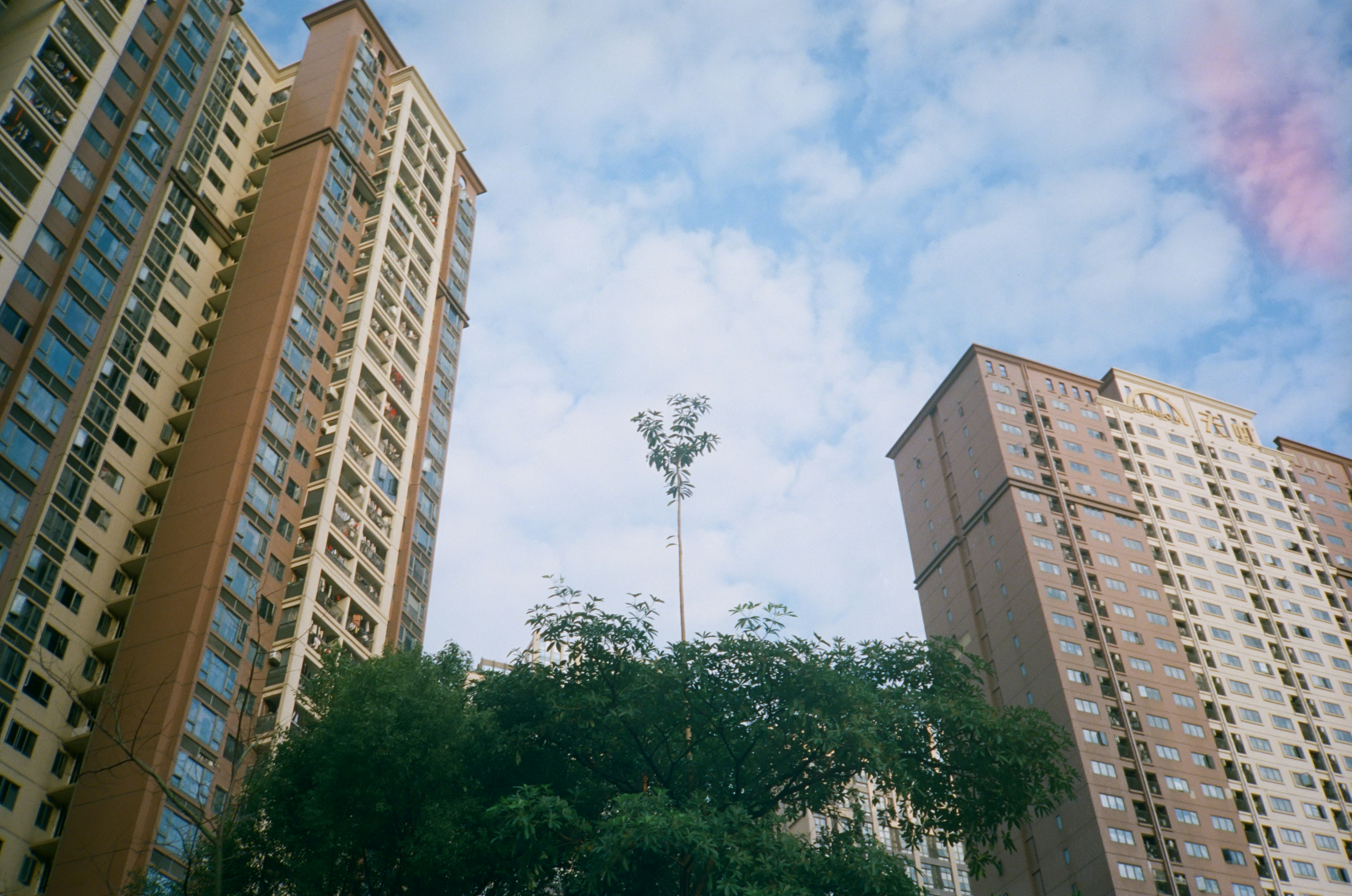 Tall apartment buildings against a cloudy sky.