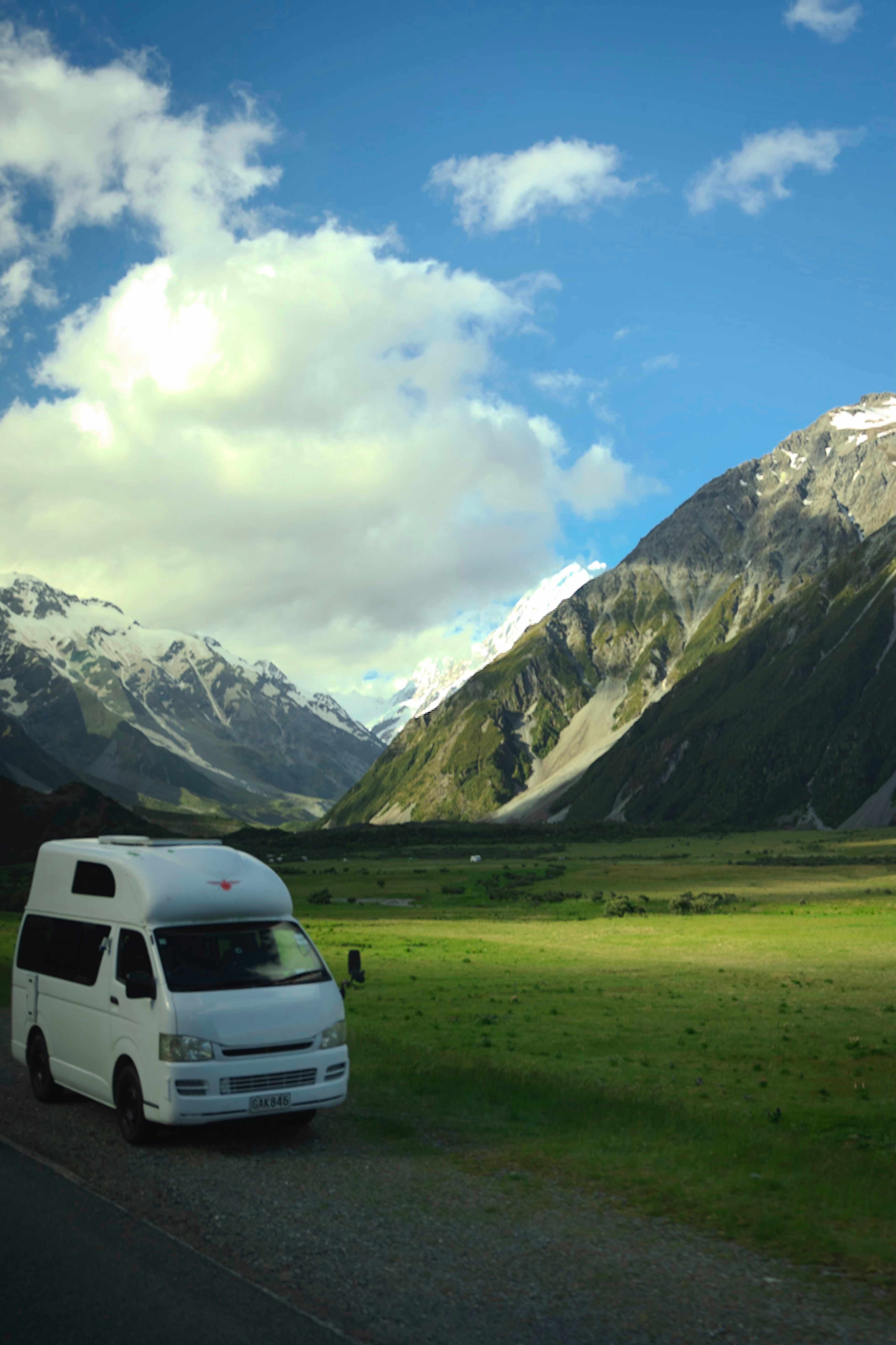 White Camper Amid Alpine Vales Under a Bright Sky