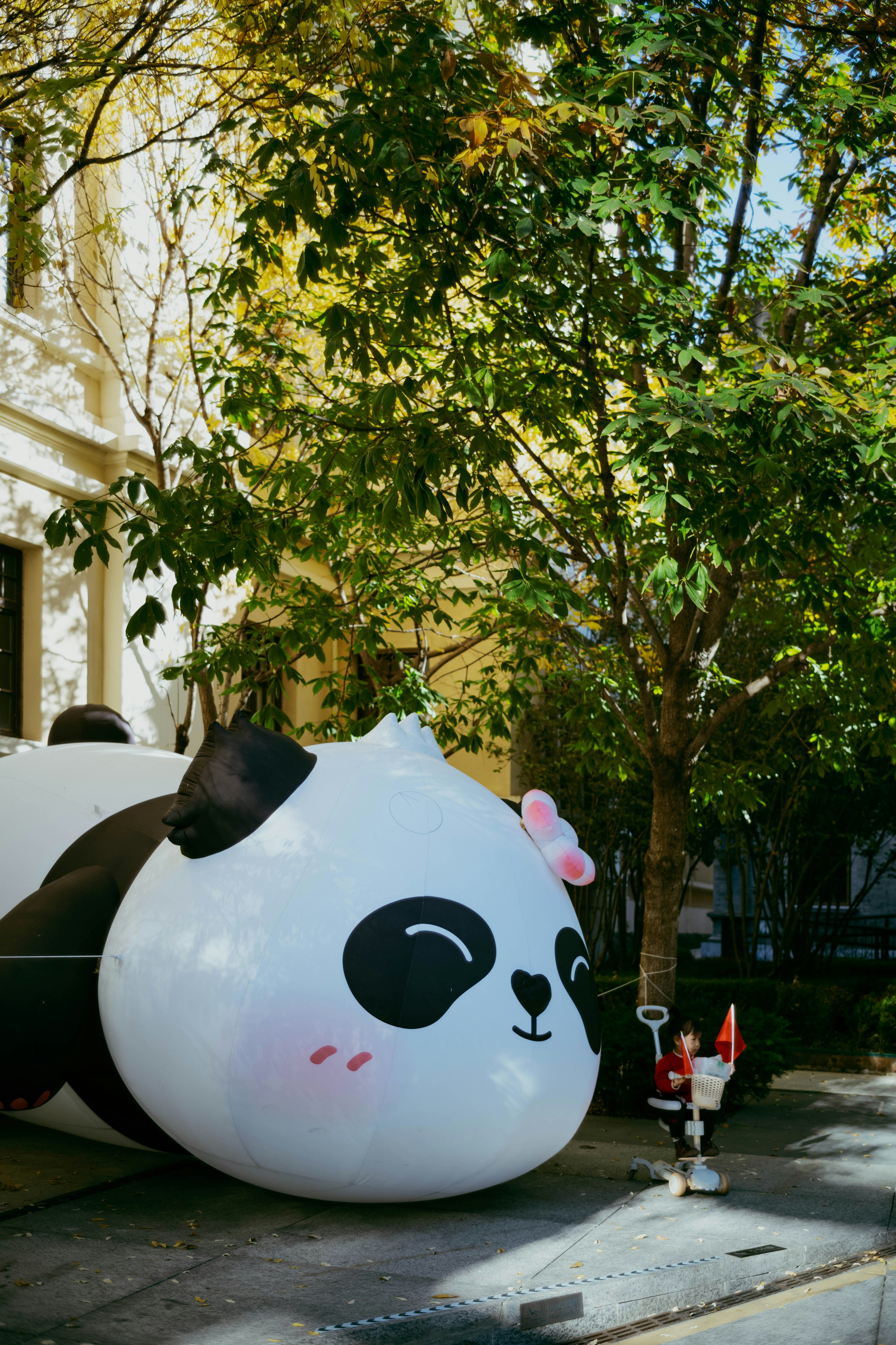 Panda Balloon at Rest Under Sunlit Foliage