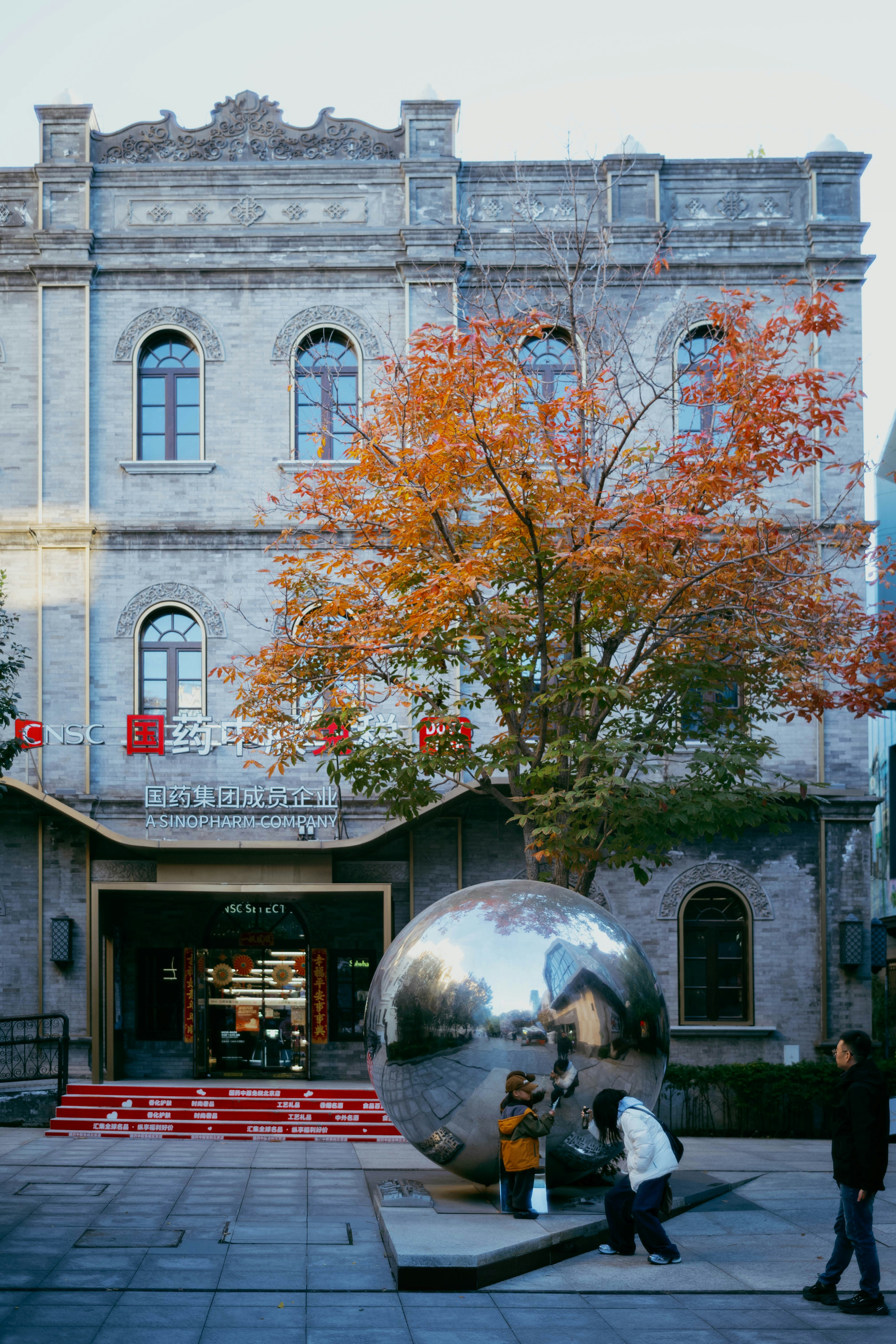 Autumn Luster by the Facade: Reflective Sphere and City Pulse
