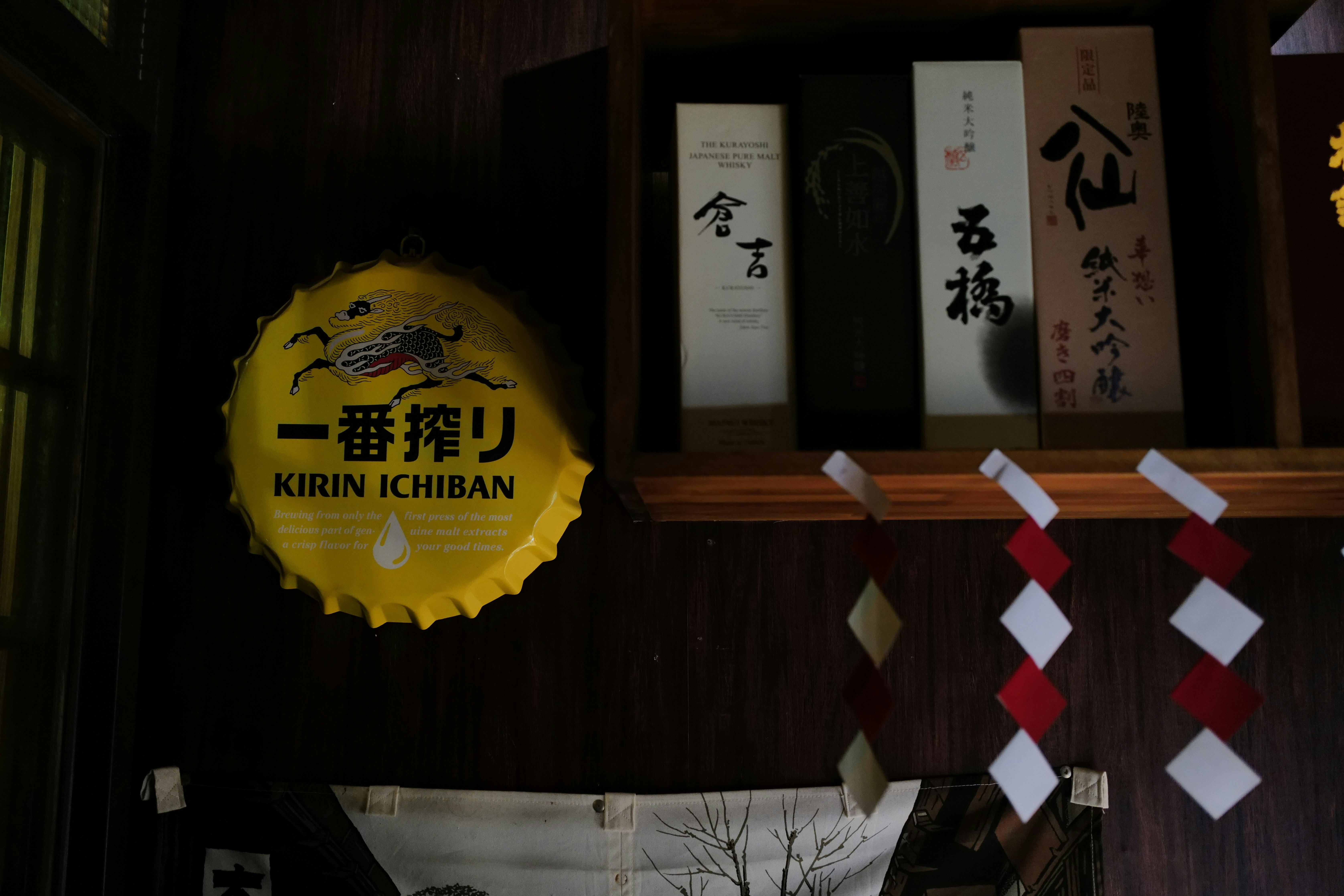 Yellow Crown: Kirin Ichiban Bottle Cap and Shimenawa Ritual Adornments in Dim Shrine