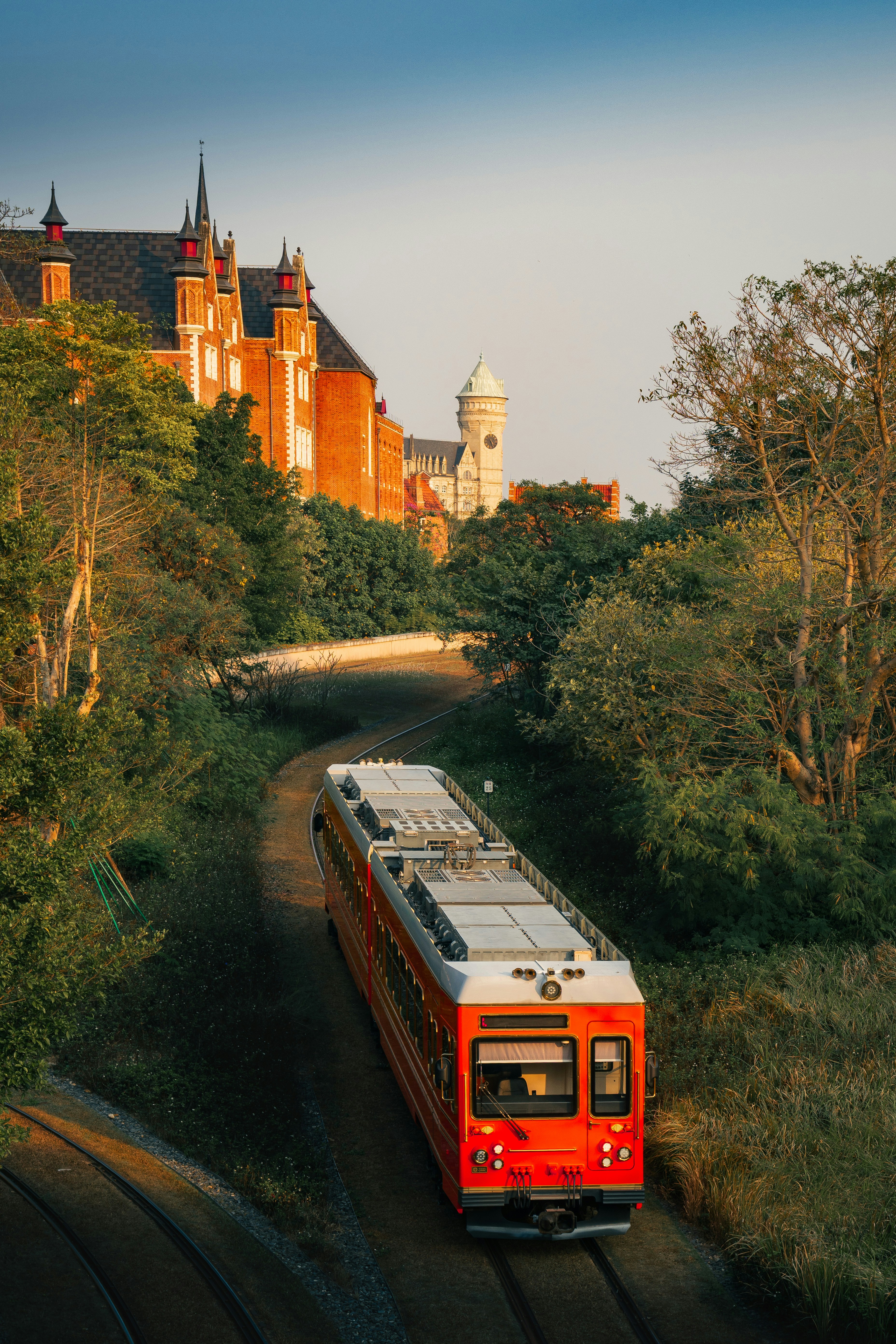Red tram threading through a hillside fortress corridor at golden hour