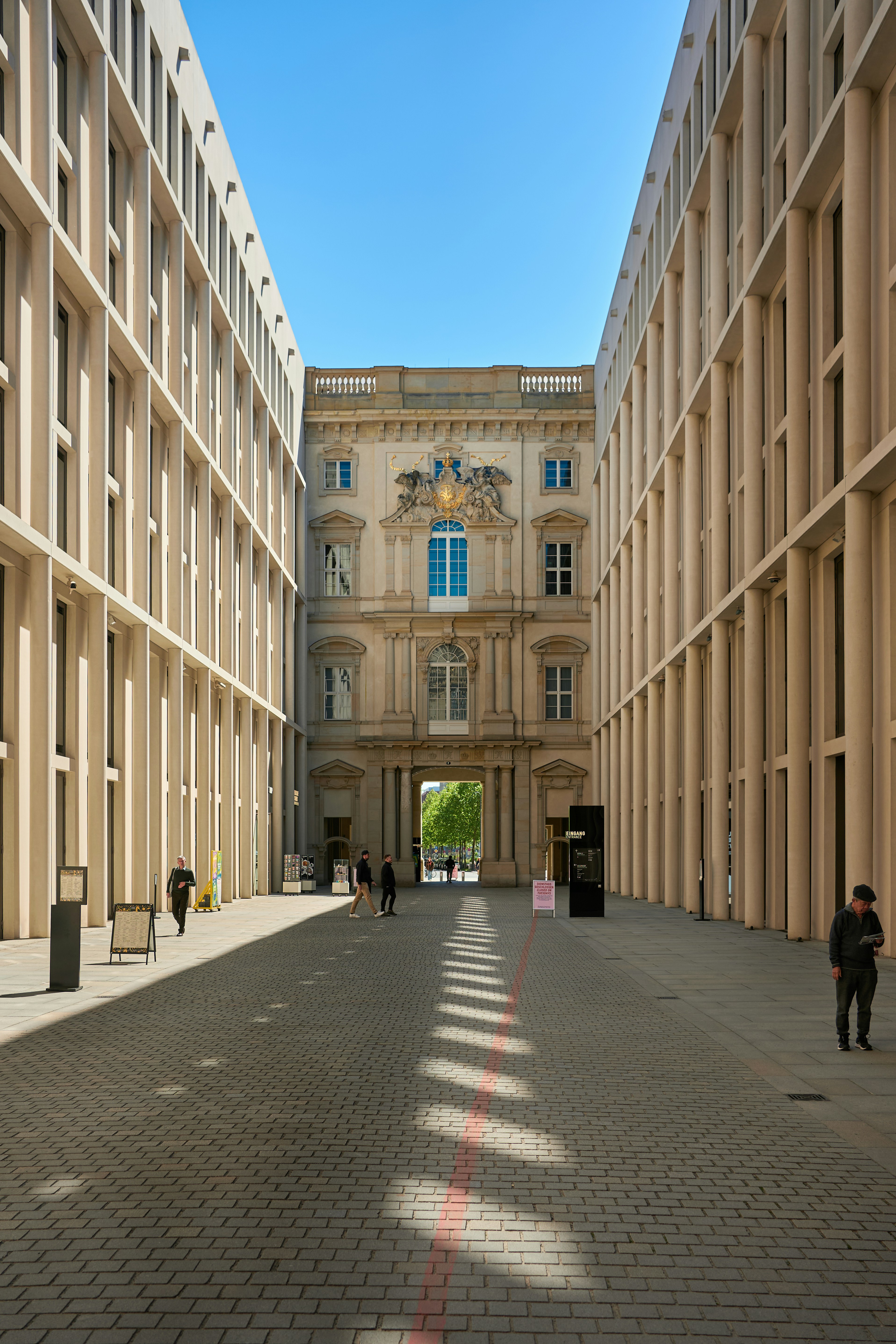 Modern buildings framing a historic facade with people walkingJakub Tomasik