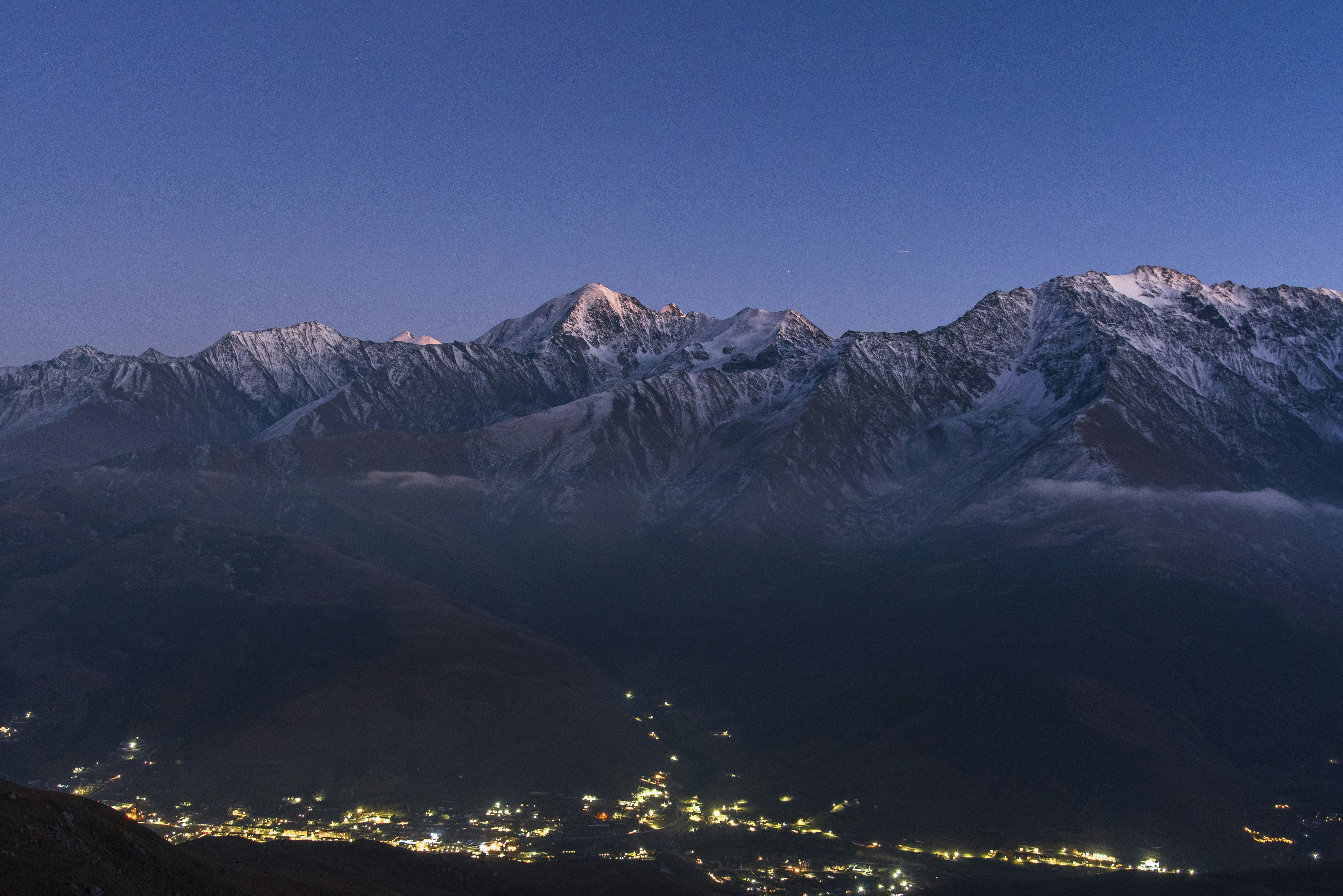 Moonlit Range: Snow-capped Peaks Loom Over a Quiet Valley