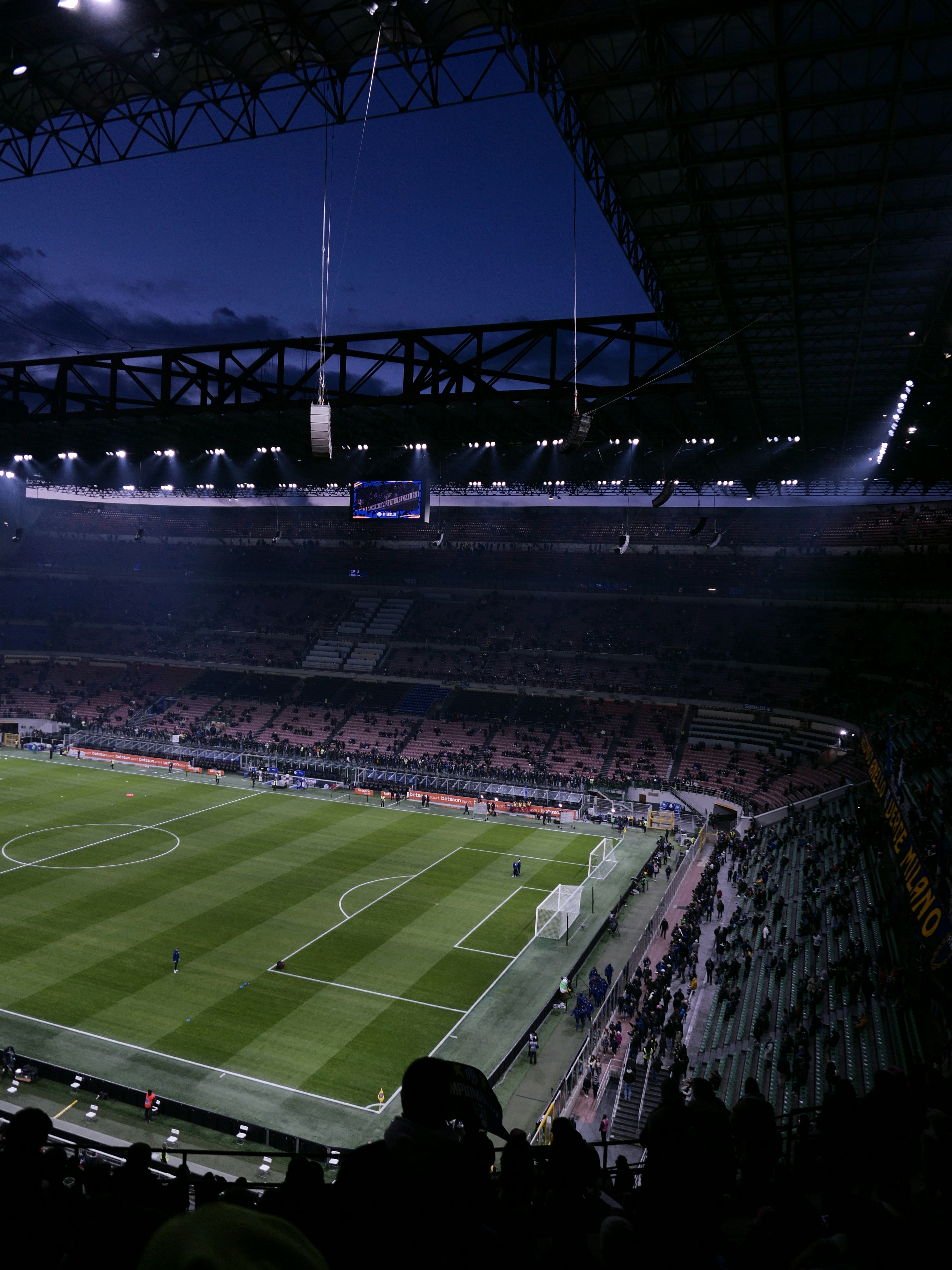Empty soccer stadium at dusk with lights on