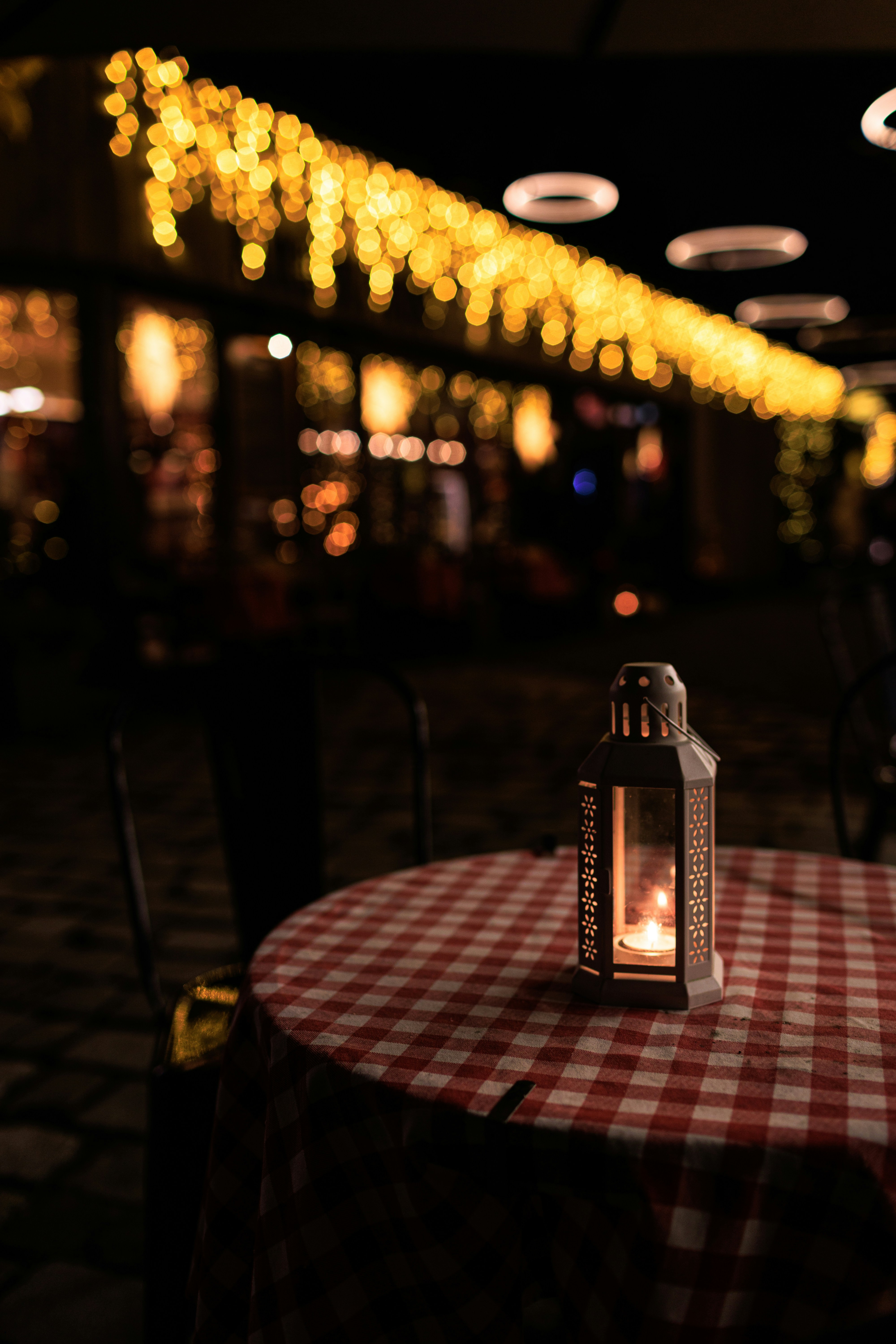 Lantern on a checkered table under warm string lights