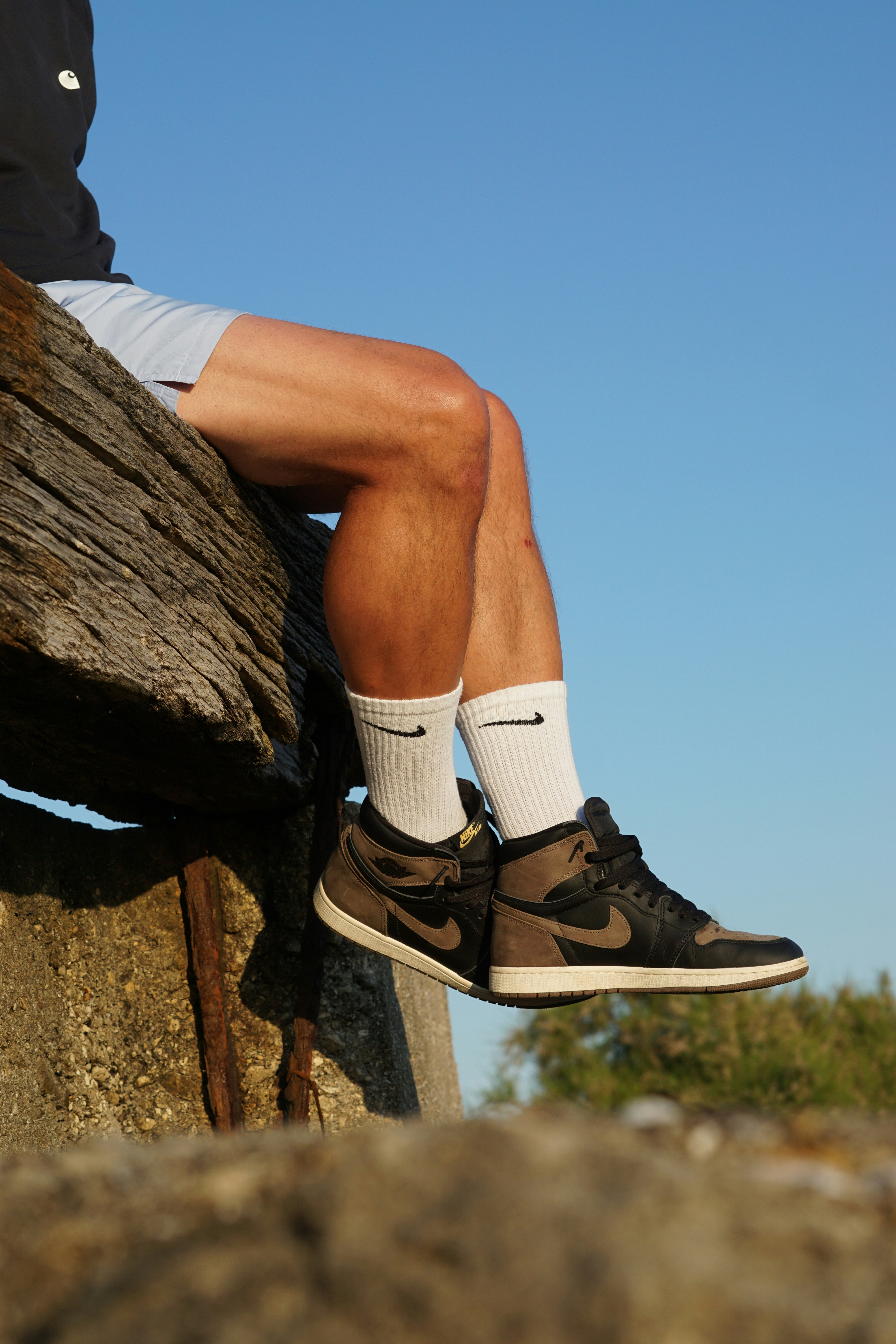 Edge of the Cliff: Sneakers, Legs, and a Clear Sky
