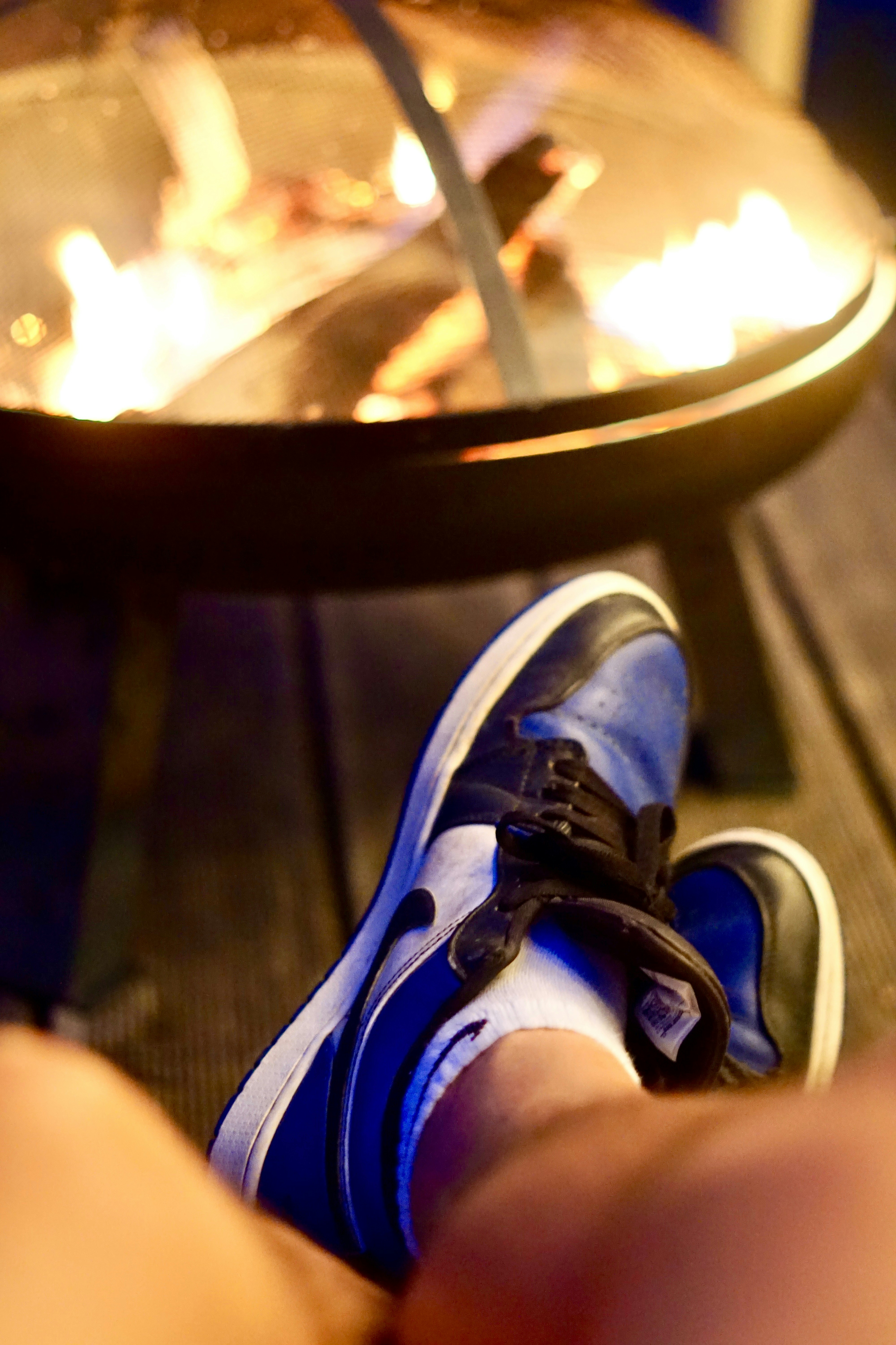 Footwear by the Fire: Blue Sneakers Resting Near Warm Flames