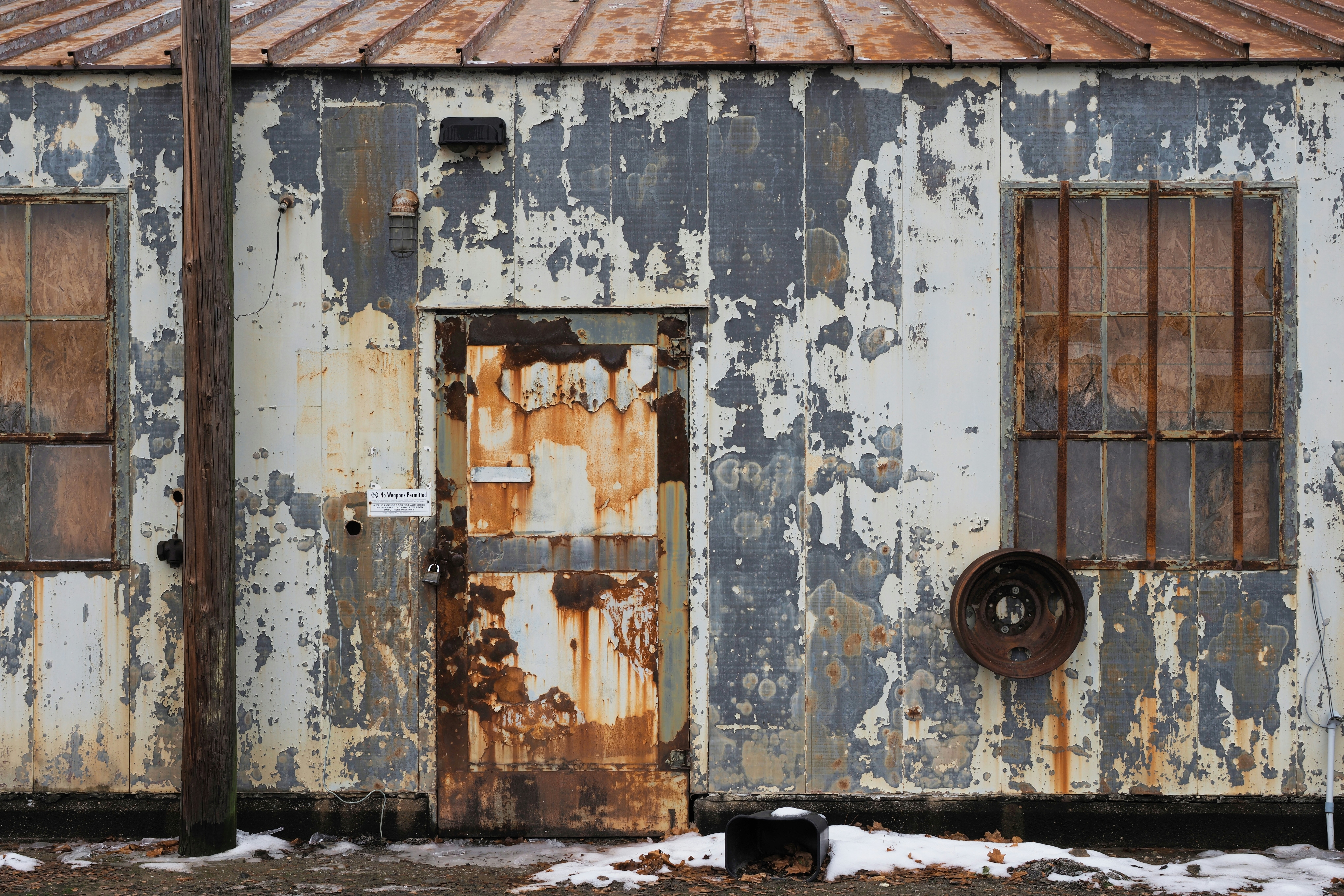 Weathered Steel: A Rusted Factory Front with Peeling Paint and Circular Outlet