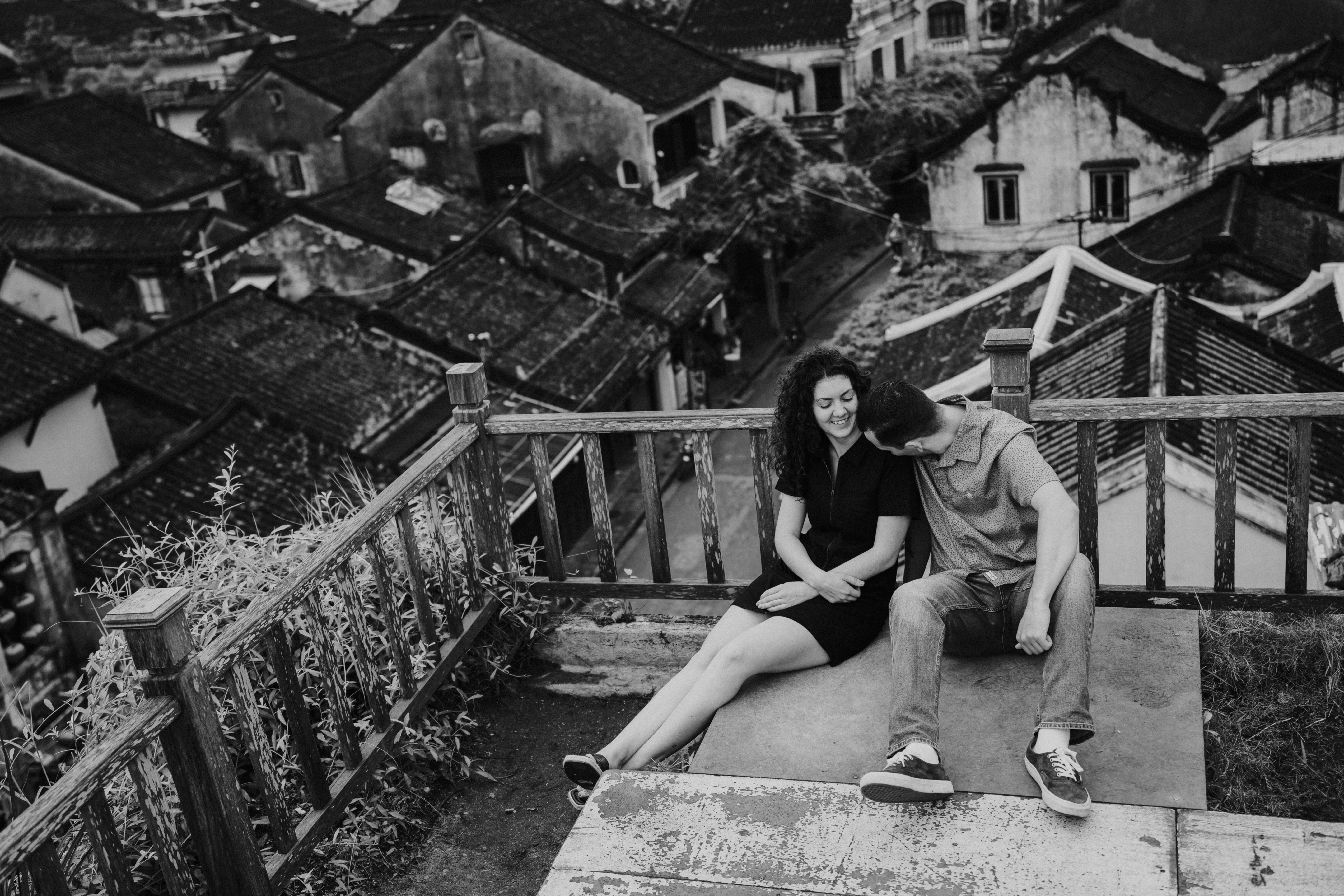 Couple on a Cliffside Balcony Over a Distant Tin Roof Town