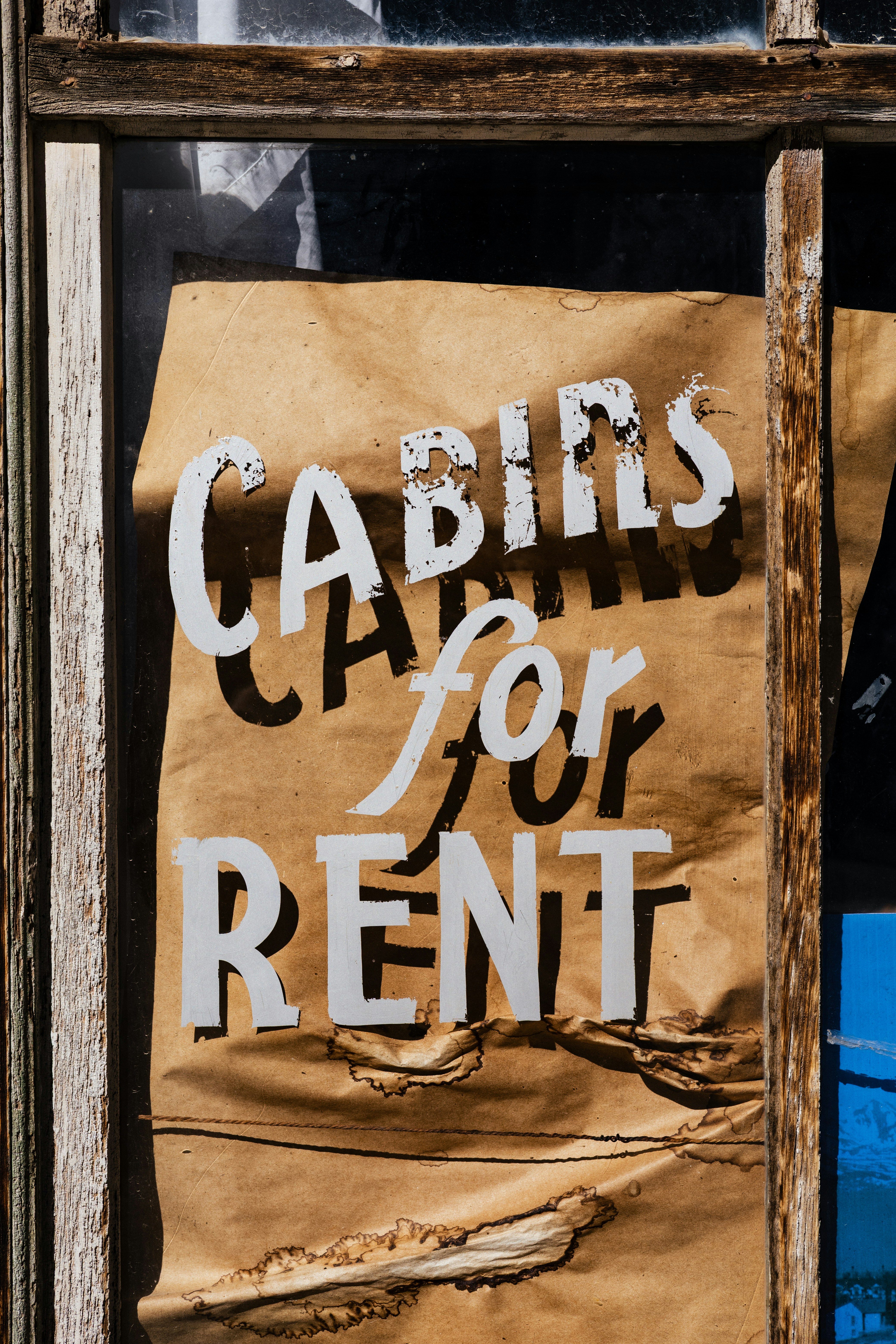 Weathered sign: Cabins for Rent peeking through a window