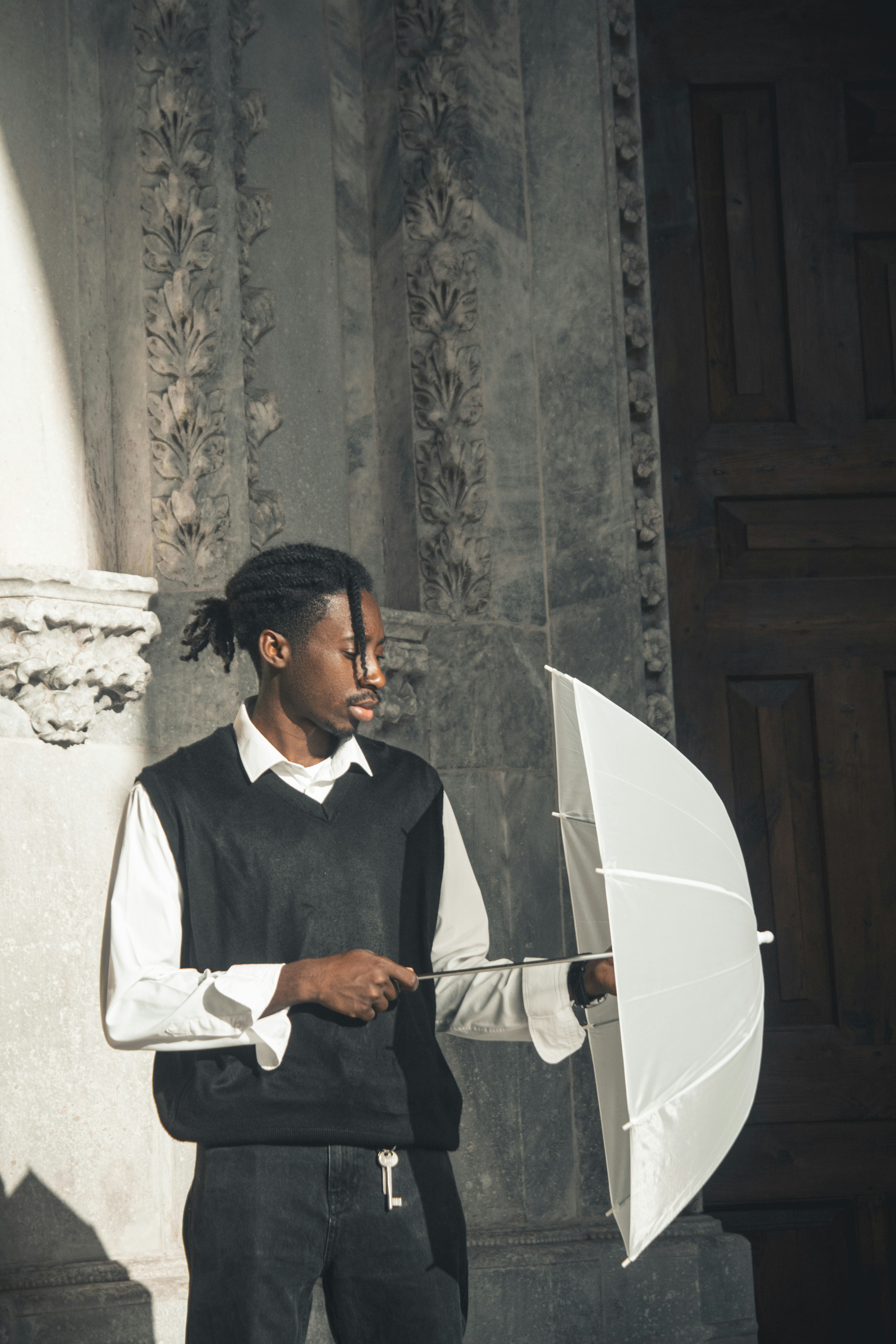 Umbrella in the doorway: a quiet portrait of a man with a white canopy
