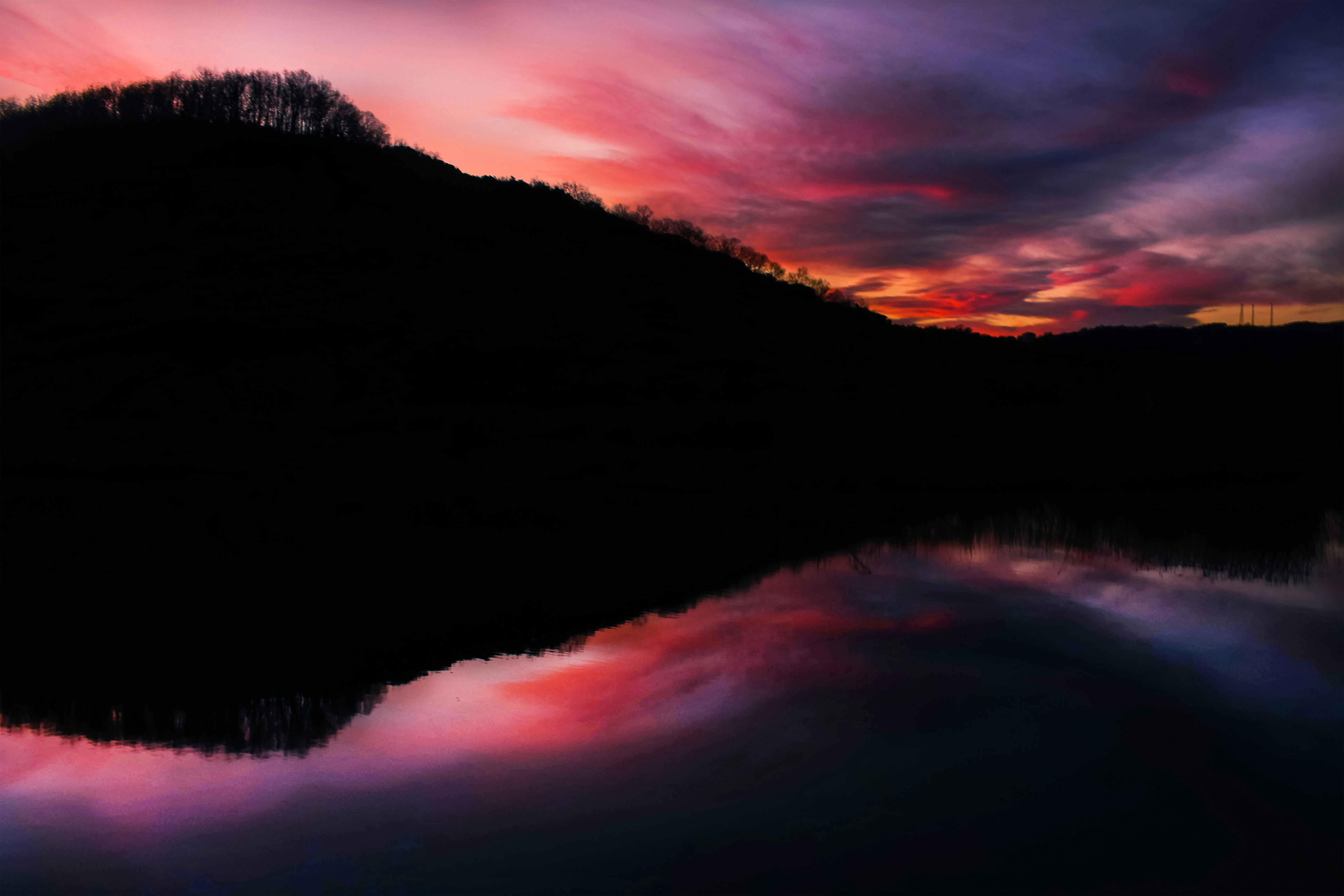 Mirror Reflection of Purple Sunrise and Hillside Silhouette