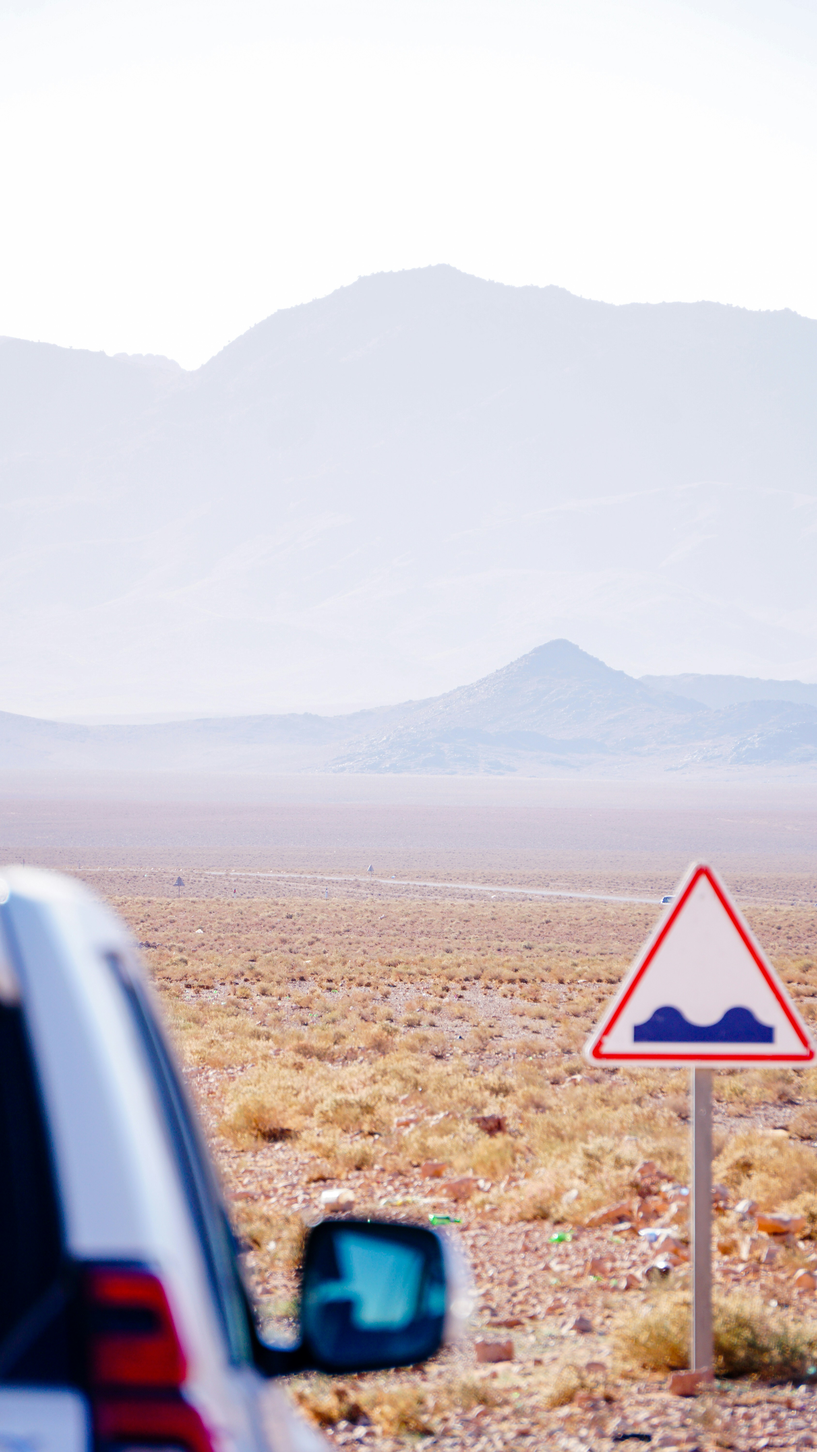 Desert Highway Sign: A Lone Drive Beneath Distant Peaks