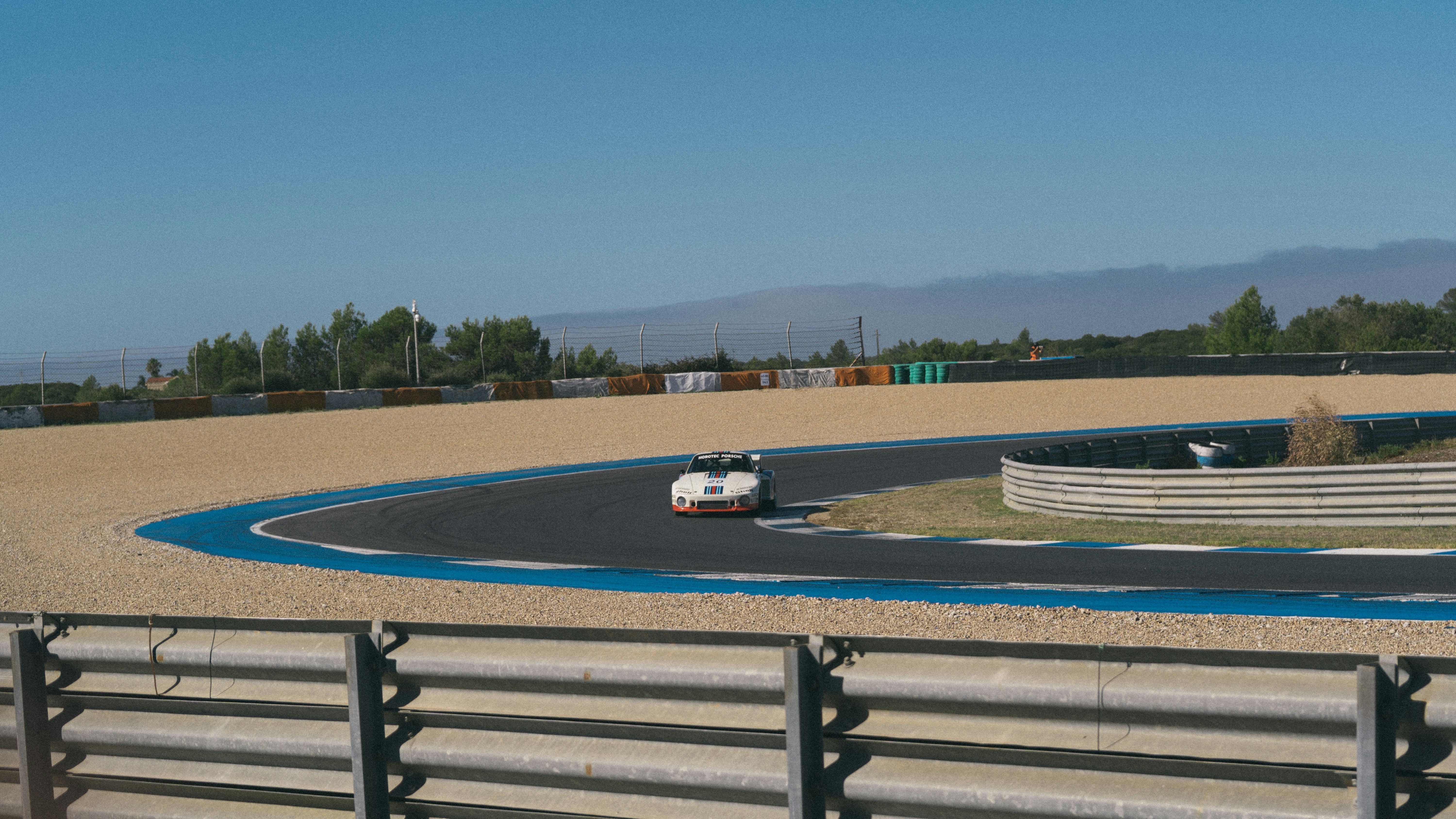 White Race Car Navigates a Blue-Rimed Hairpin at Dusk Track