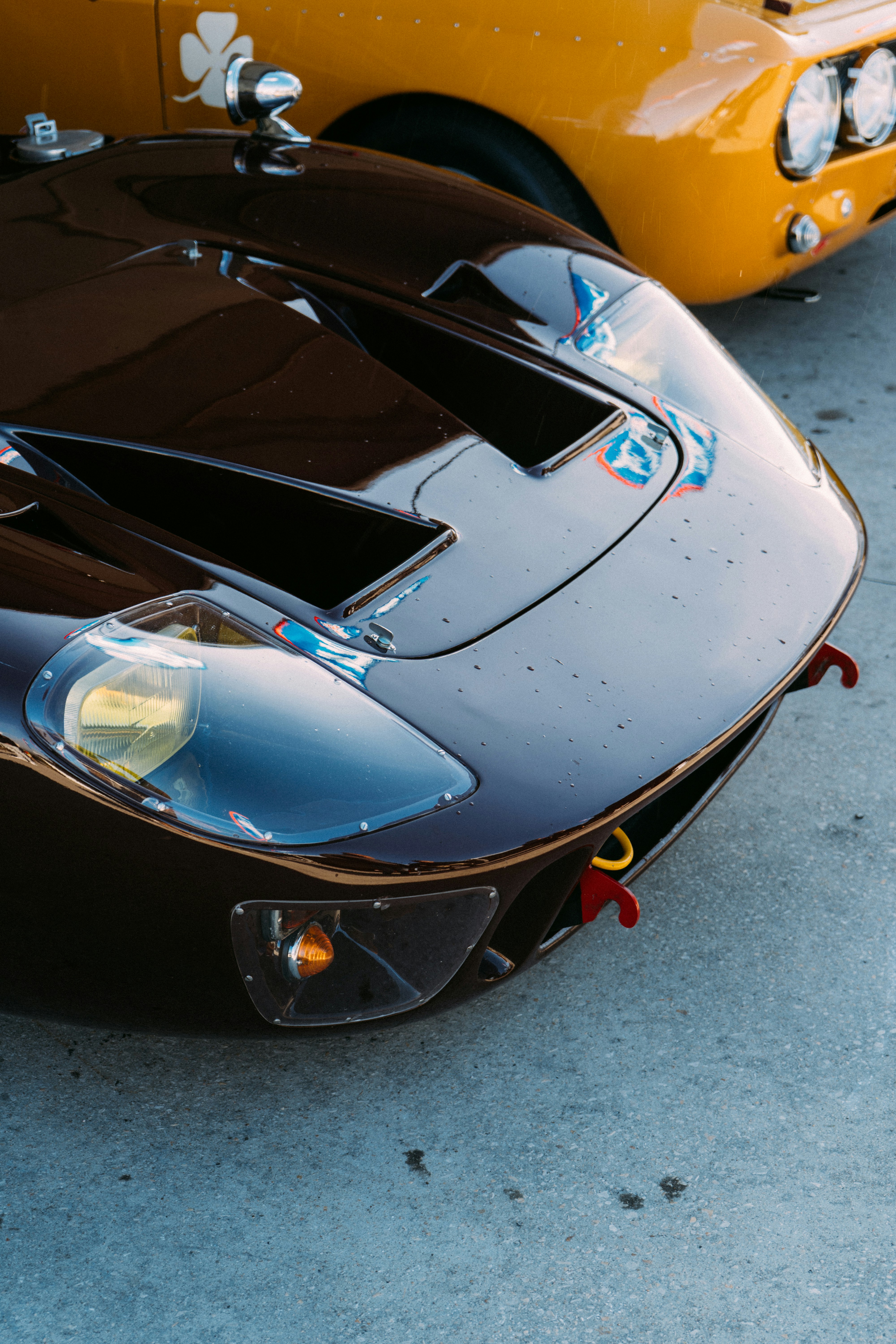 Midnight Curves: A Sleek Black Hypercar Framed by a Golden Bus
