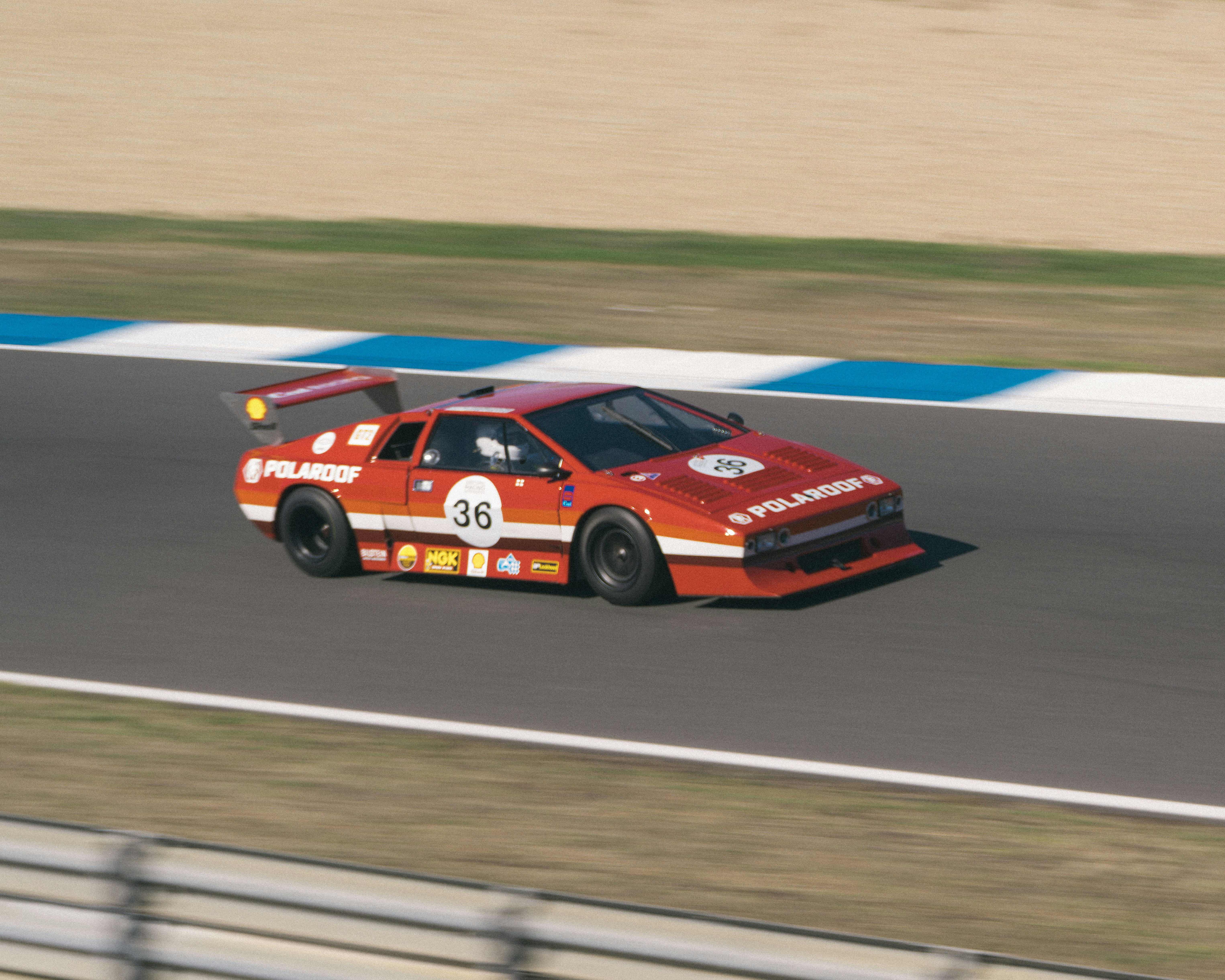 Red Race Car in Mid-Rapide Cornering on a Race Track