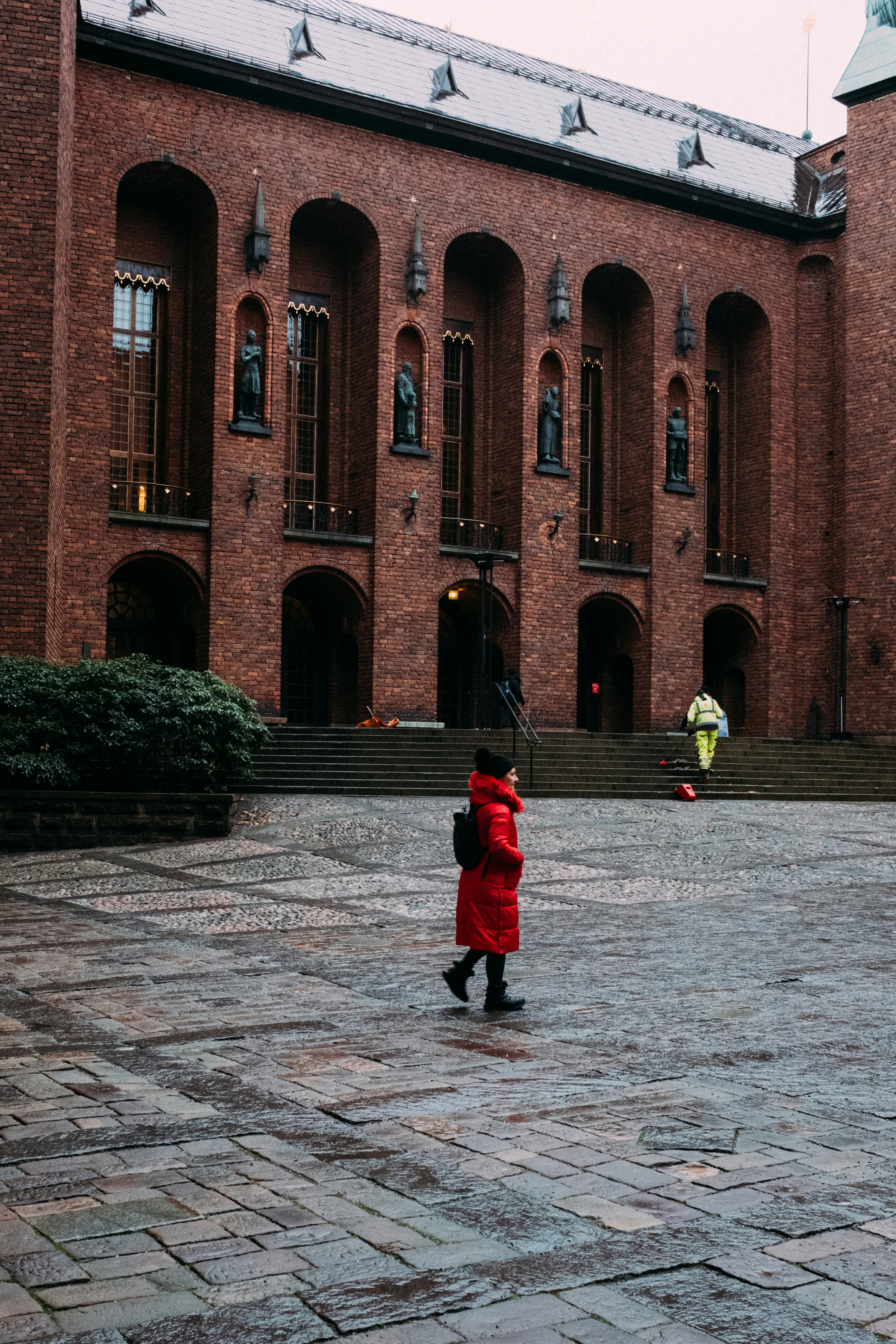 Red-Cloaked Wanderer Before a Brick Monolith