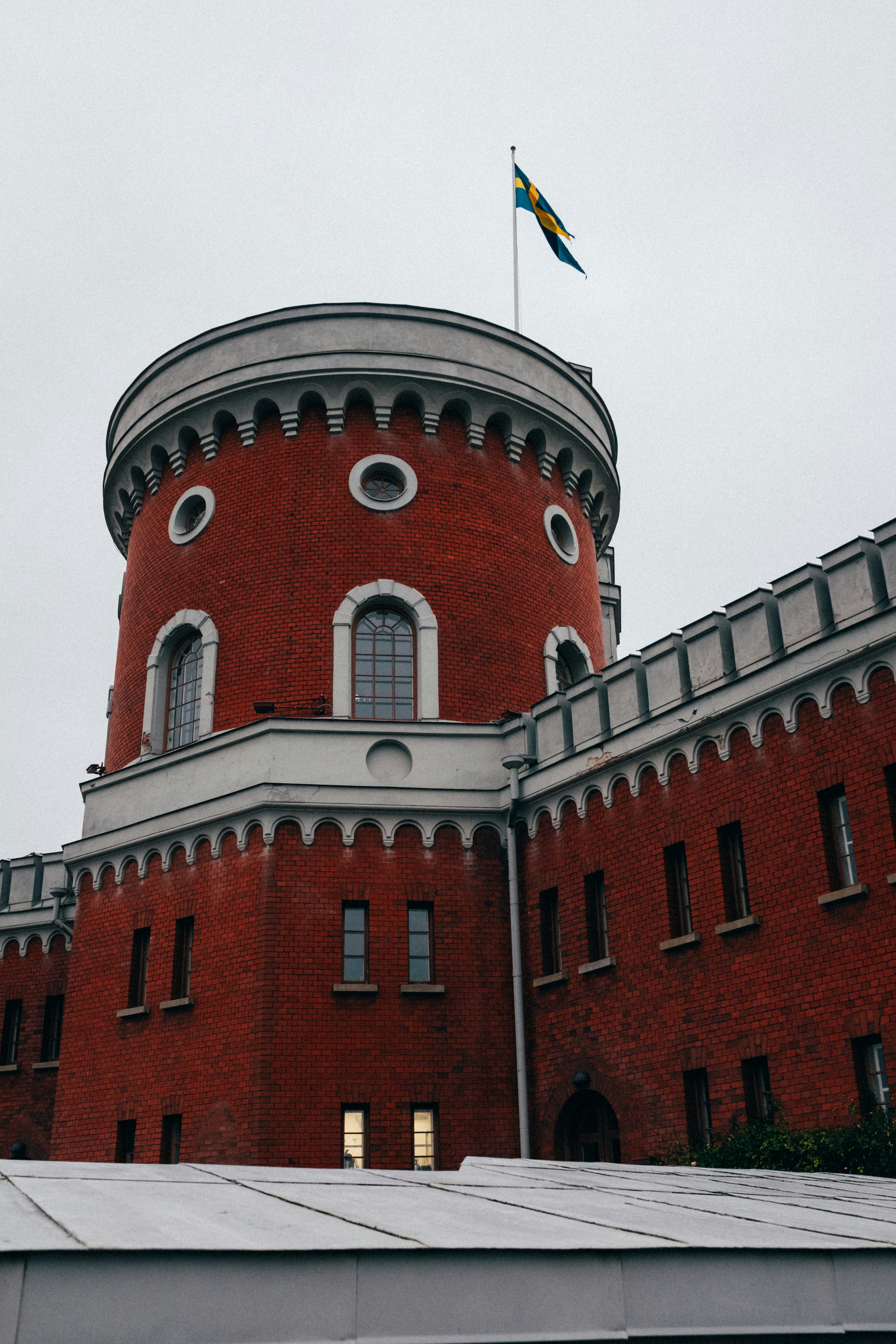 Red Brick Turret Under Flag: A Historic Castle Facade Soars Against Grey Skies