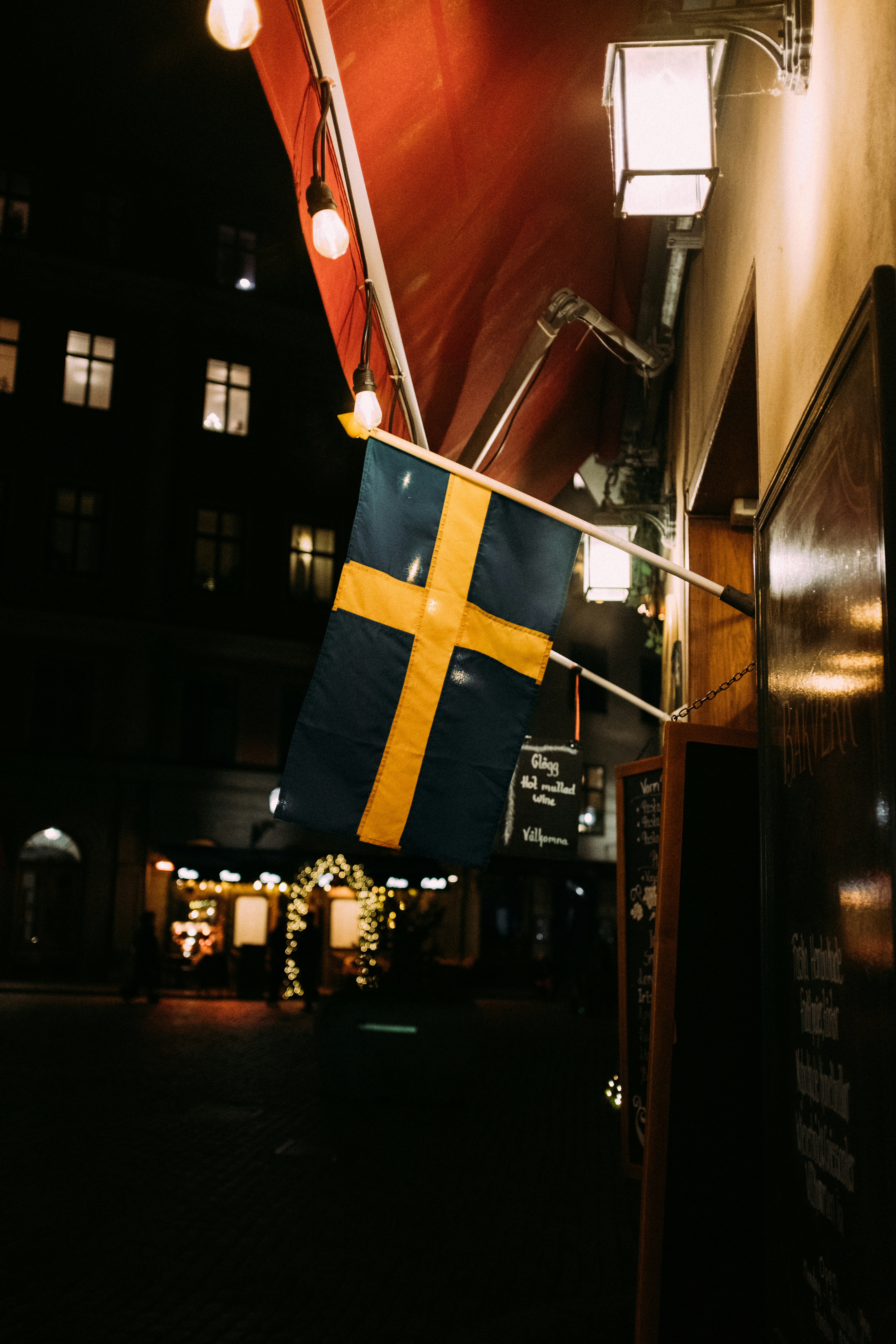 Swedish Flag in a Dimly Lit Street Aglow with Festive Lights