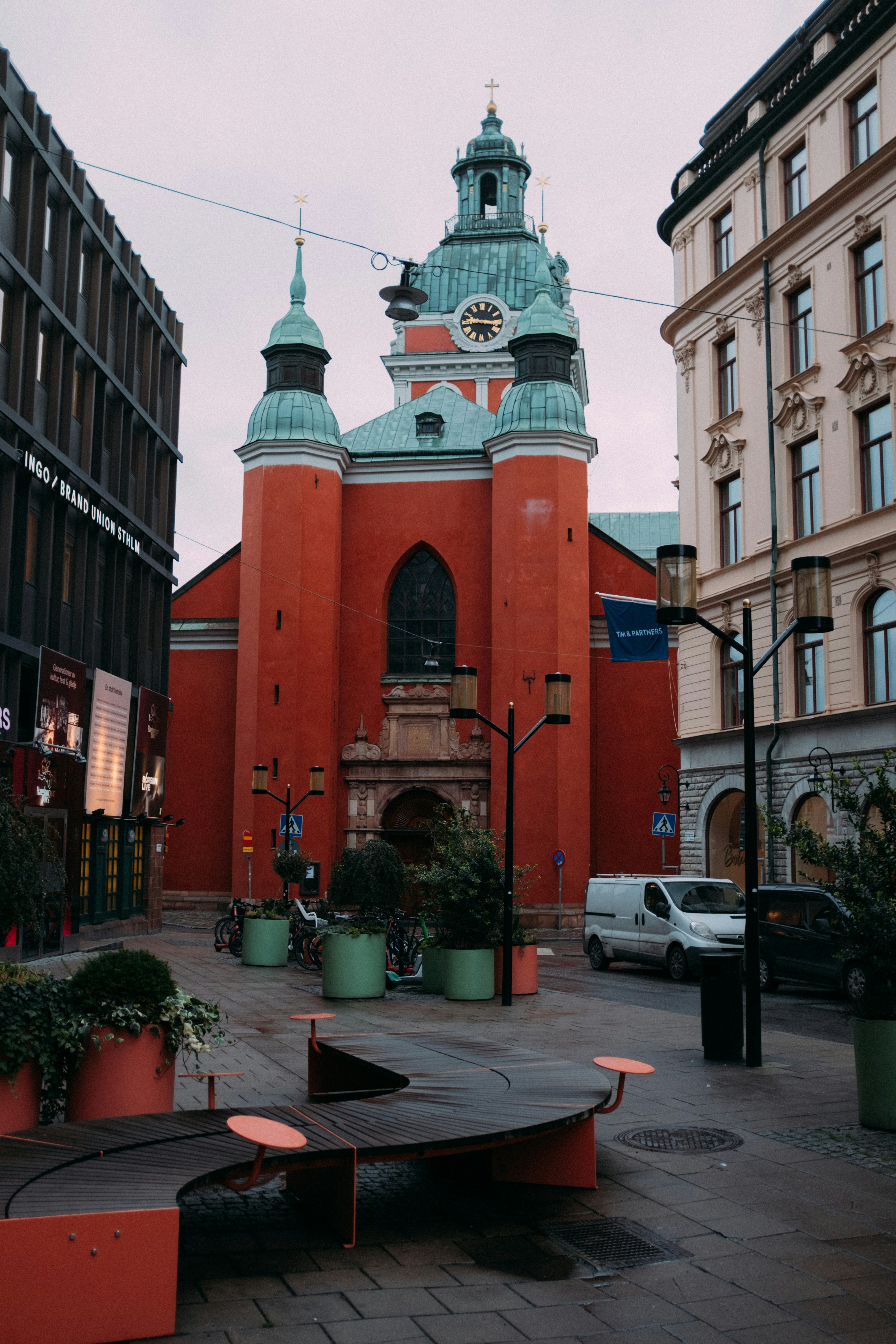 Red-brick church looms over a cobblestone plaza with modern storefronts