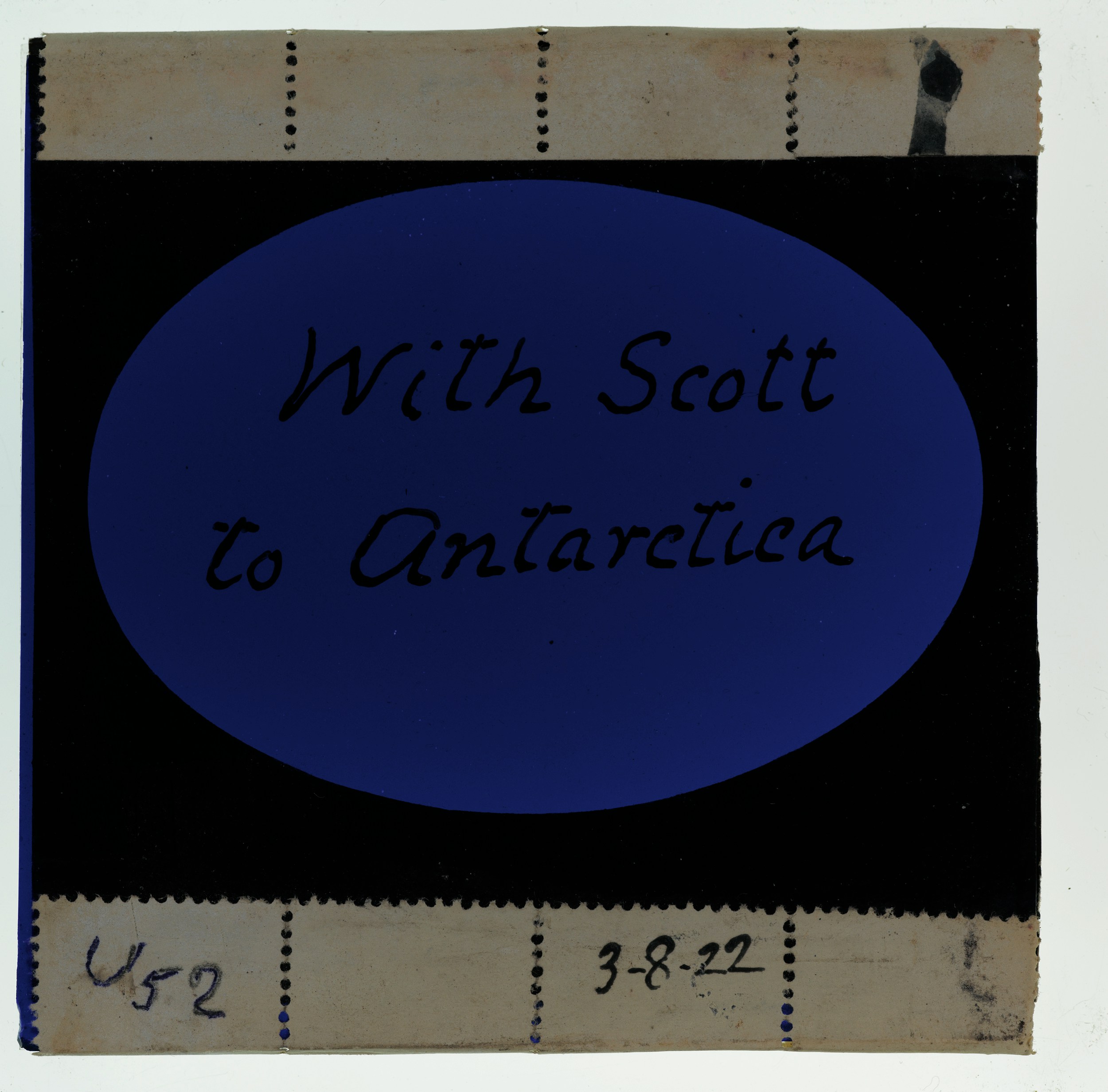 A lantern slide produced by Clement Lindley Wragge (b.1852, d.1922), dated 3 August 1922. The slide shows handwritten text within an oval on a deep royal blue tinted plate, 'With Scott to Antartica'. Shared by Auckland War Memorial Museum, Tāmaki Paenga Hira, as part of the Clement Lindley Wragge collection