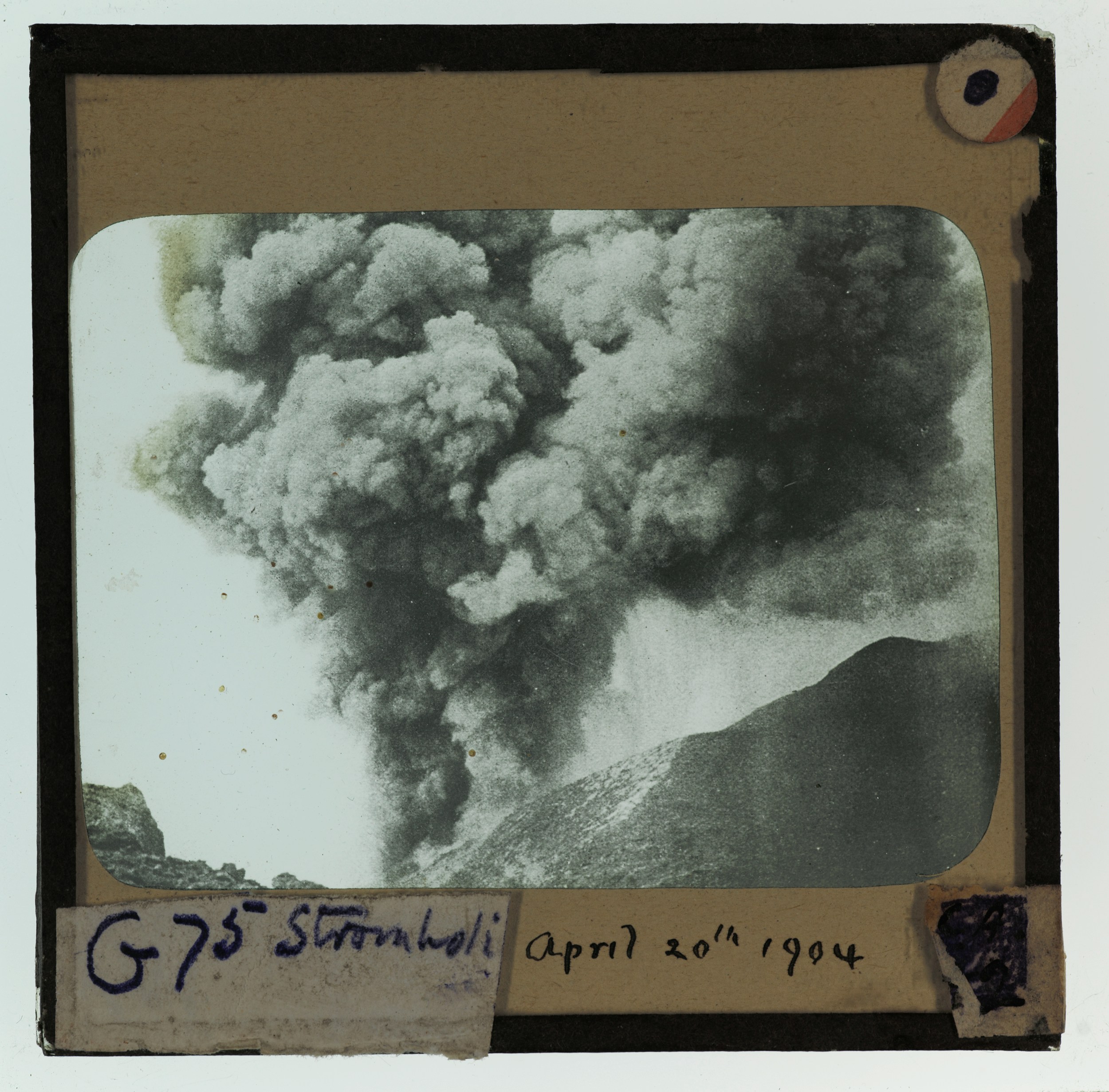A lantern slide produced by Clement Lindley Wragge (b.1852, d.1922), dated 20 April 1904.The slide depicts a large plume of smoke, dust, and ash emerging from the side of Mount Stromboli. Shared by Auckland War Memorial Museum, Tāmaki Paenga Hira, as part of the Clement Lindley Wragge collection. 235988|PH-1984-1-LS78-3-59|75. No known copyright restrictions. https://www.aucklandmuseum.com/discover/collections/record/1033227