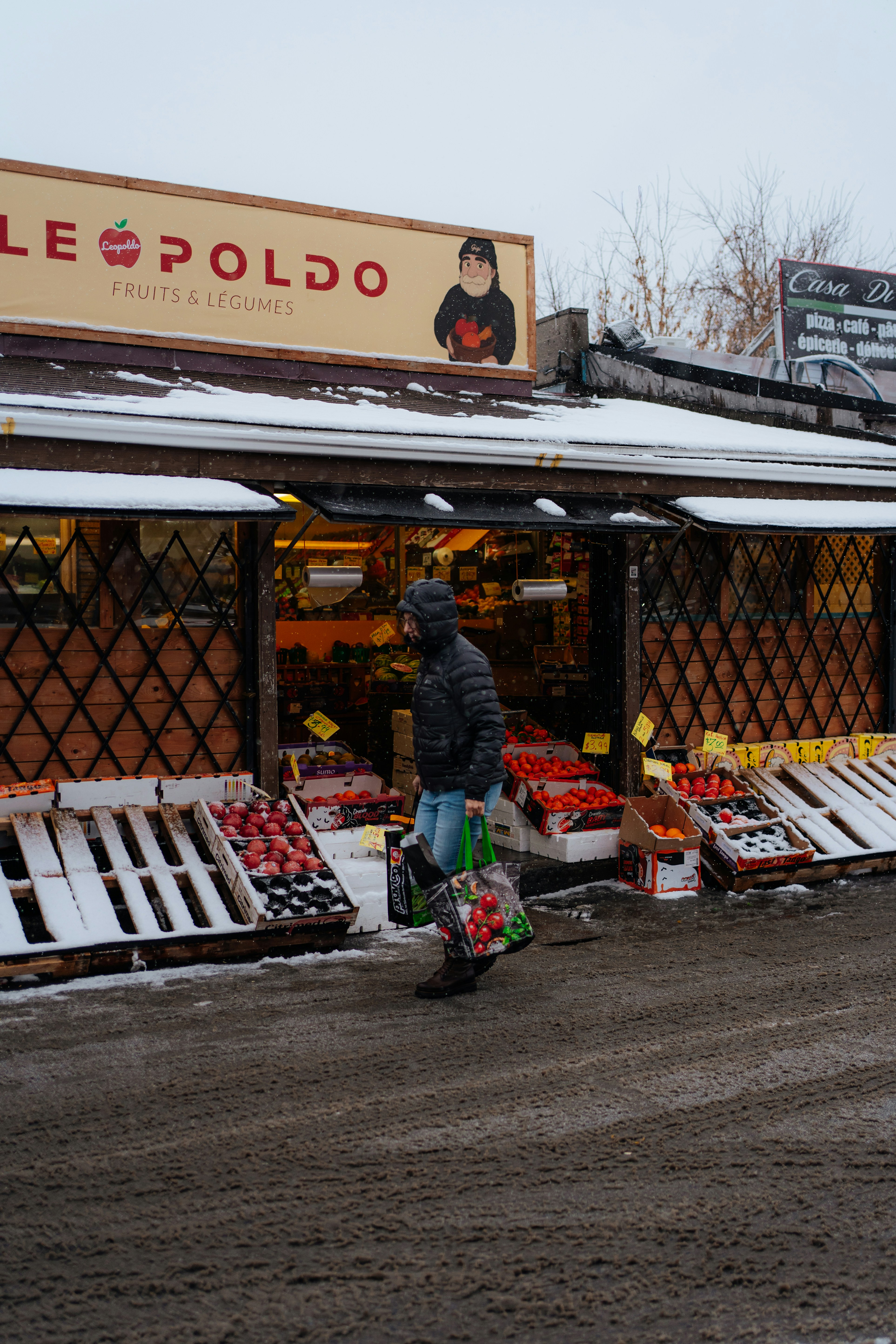 Snowy Market Walk: A Shopper Passes Fresh Produce Outside a Rustic Fruit Stand