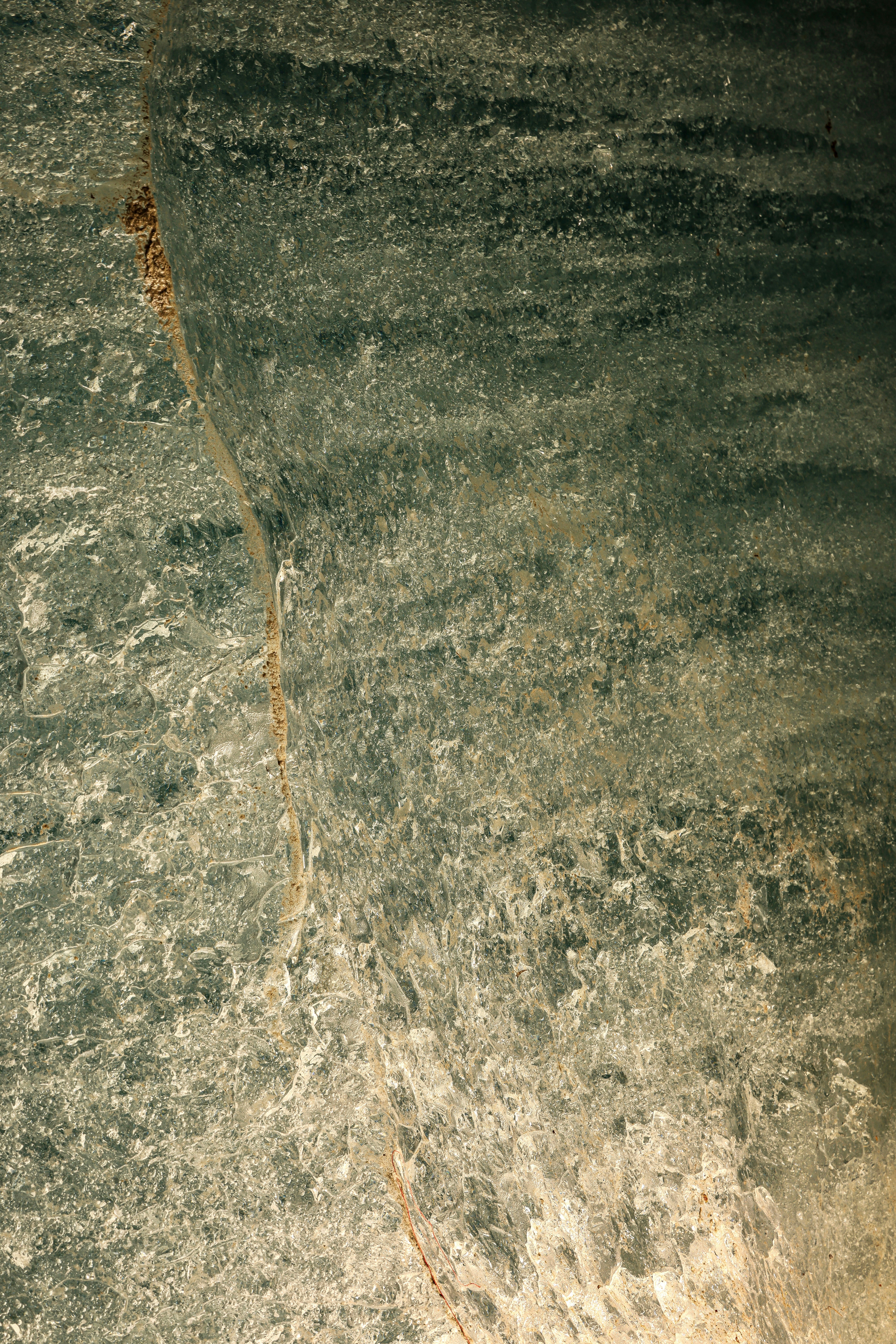 Crack in a weathered stone wall threads through a dusty cave-like surface